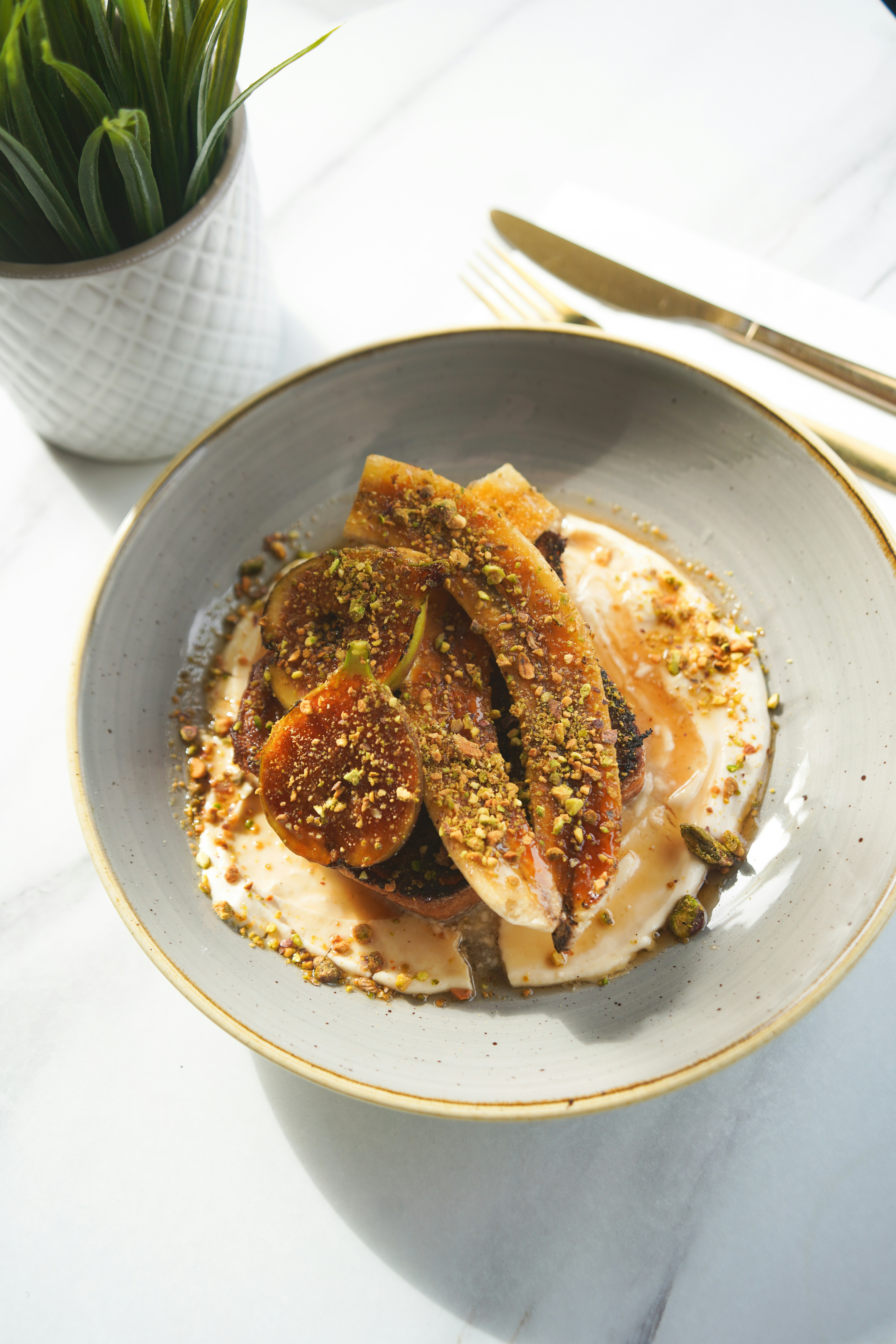 Fig and Pistachio Crumble over Creamy Tonks of Yogurt in a Gray Ceramic Bowl