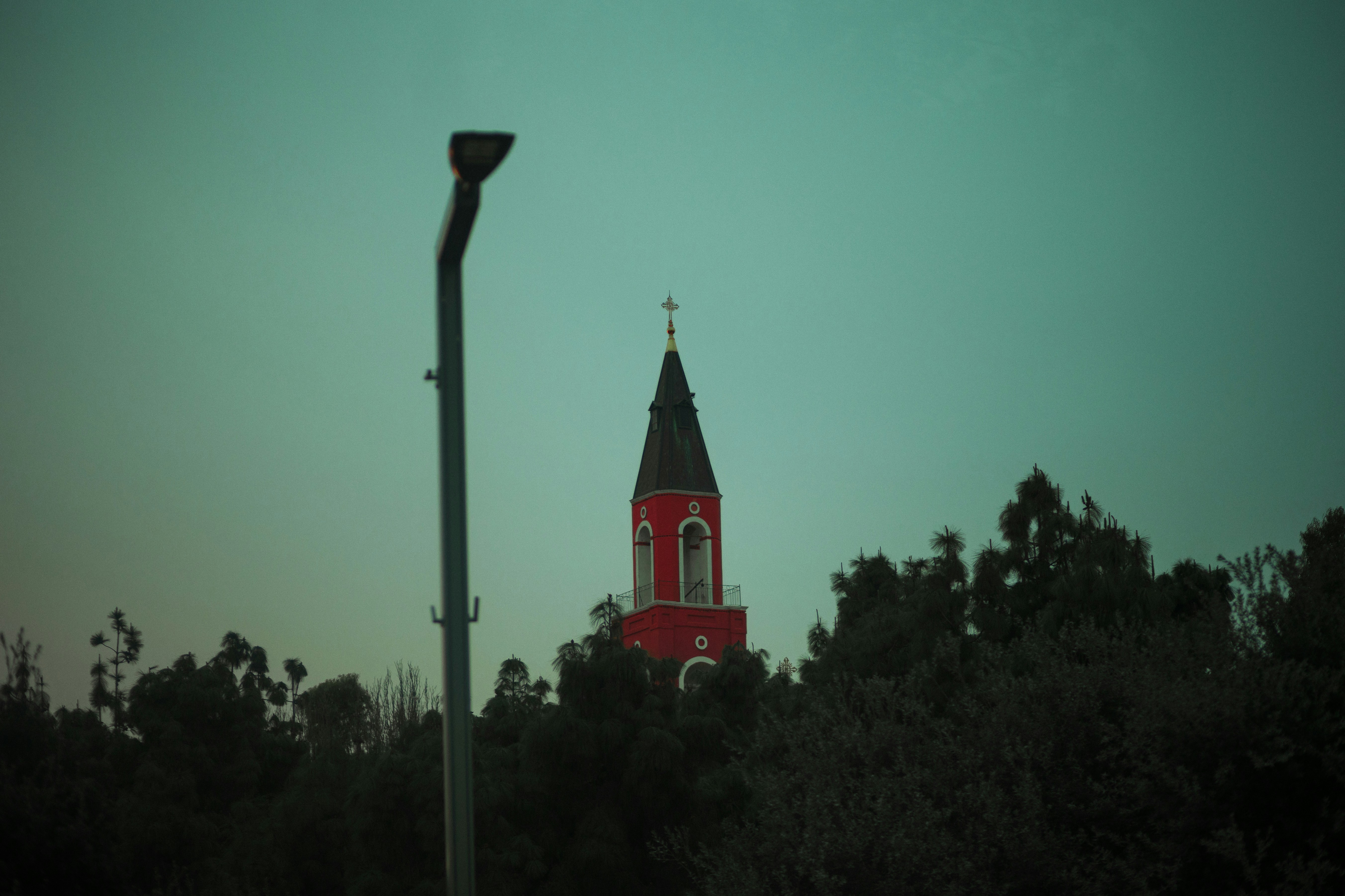 Red Clock Tower Rising Above Darkened Trees