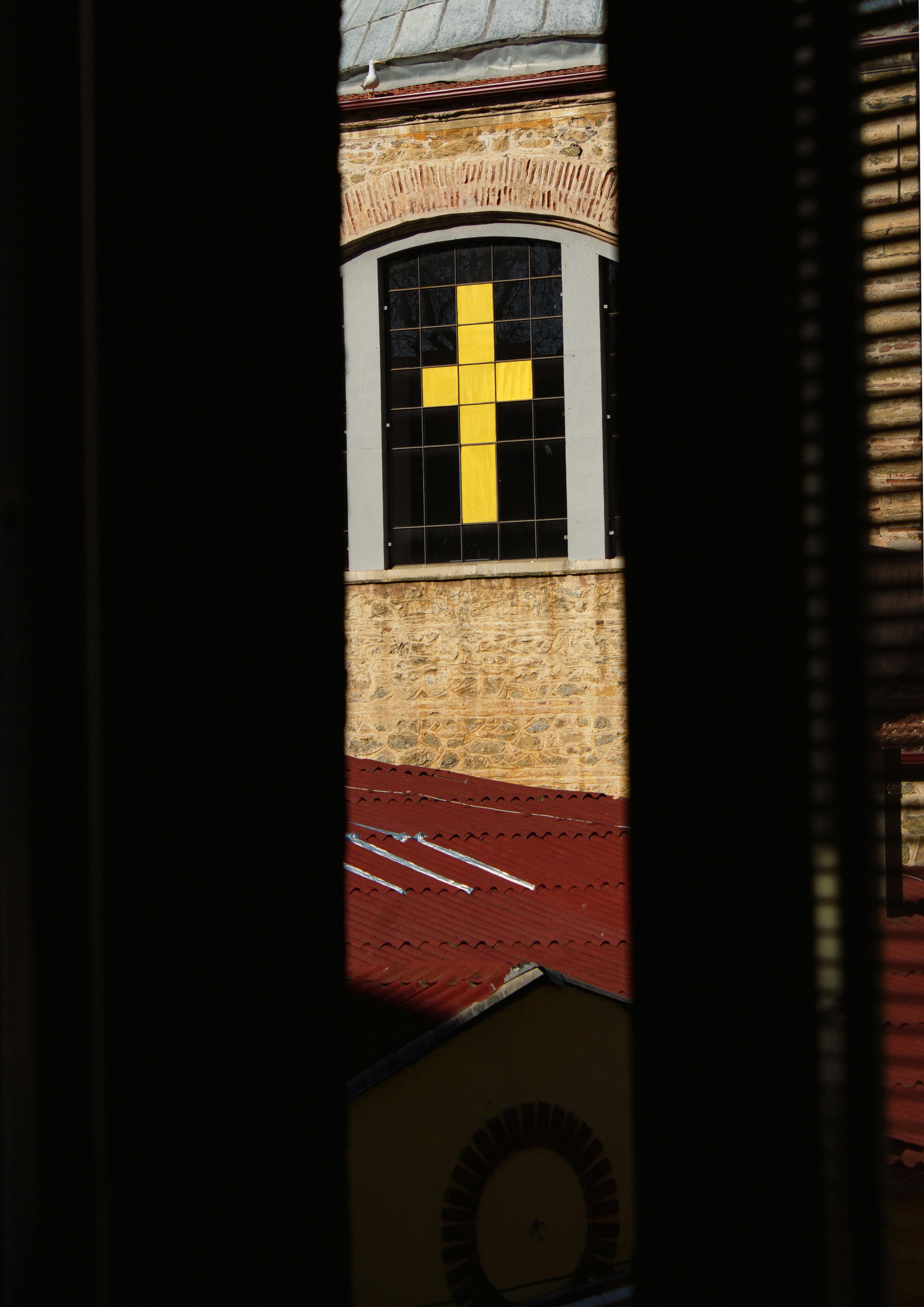 Yellow Cross Window Framed by Dark Slats