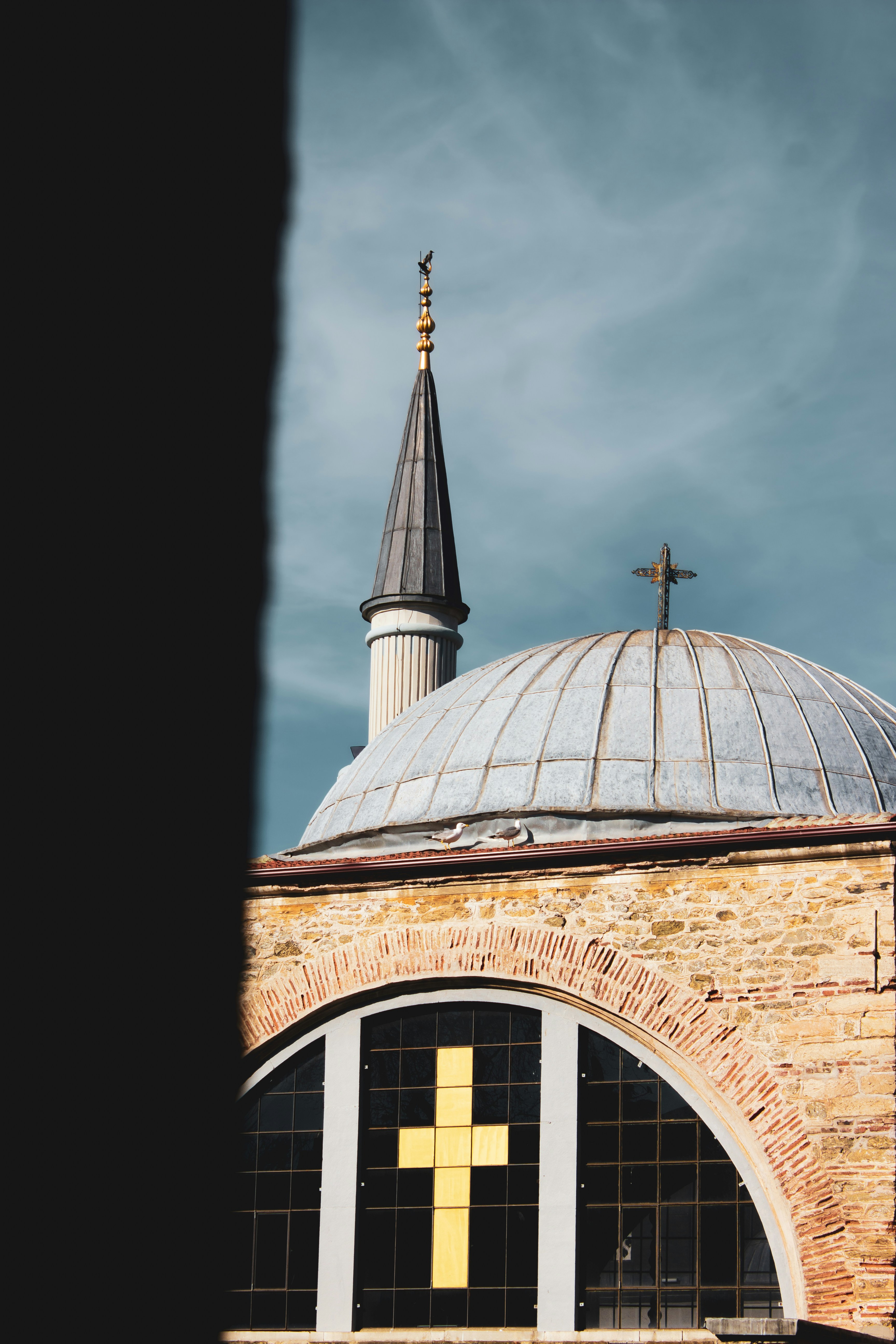 Cross and Dome: A vantage peek over brick arch and pale domed roof