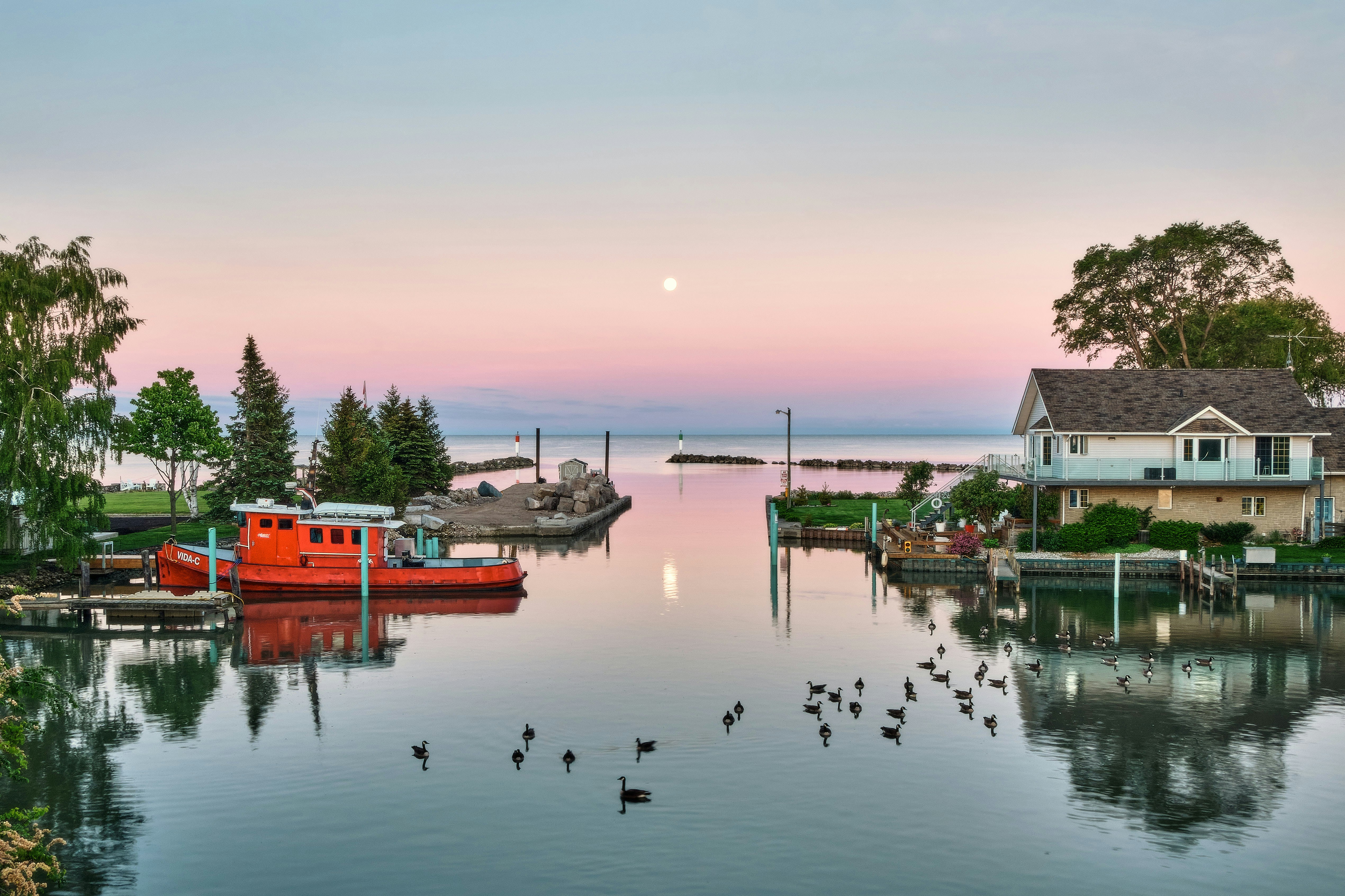 Sunrise Over a Quiet Harbor: Reflections, Boats, and a Snow-Cap Greenhouse