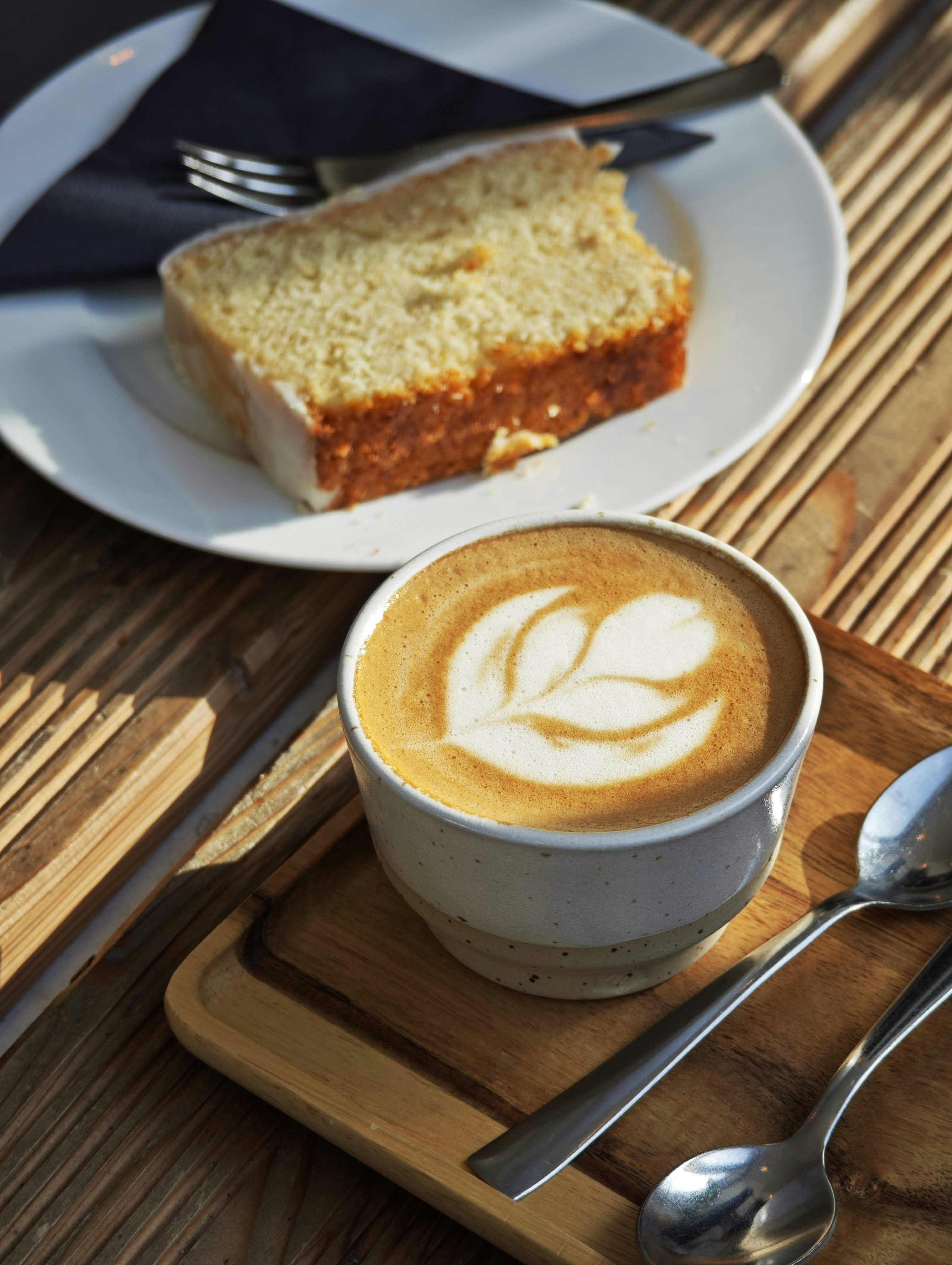 Latte Art Quiet Moment: Cup in Focus with Slice of Cake in the Background