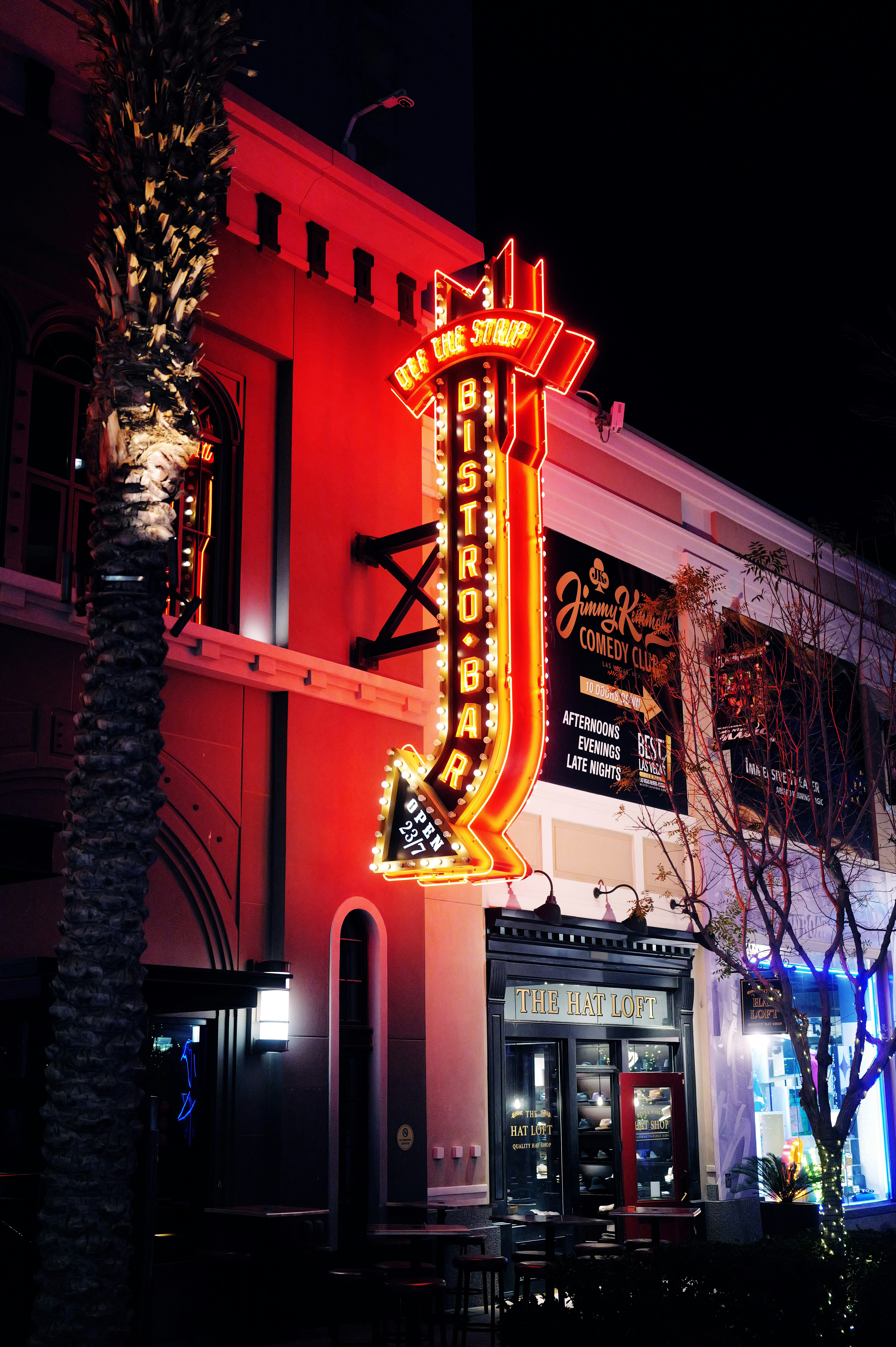 Neon Signage Casts Red Hue Across Night Street Façade