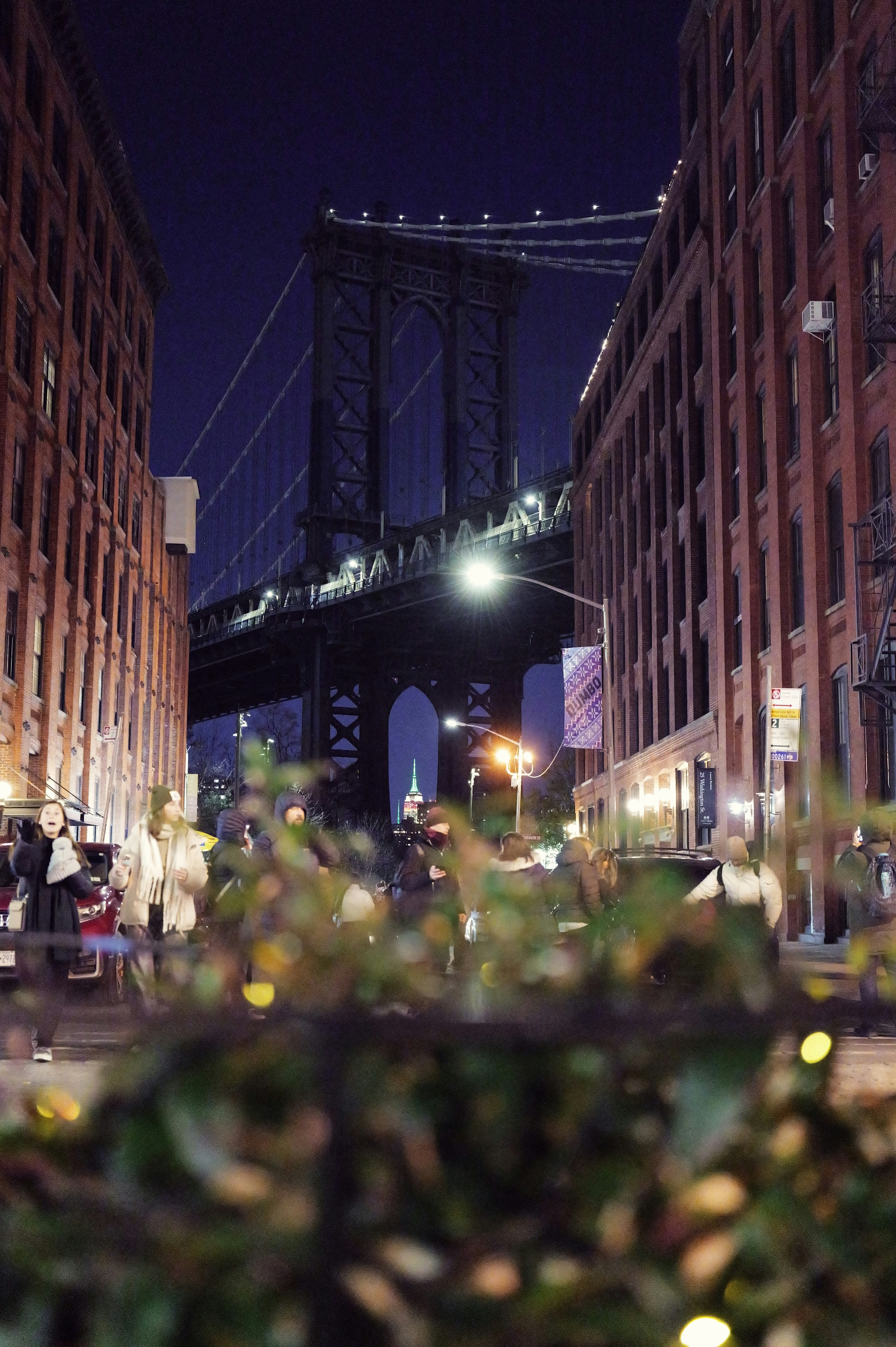 Urban nocturne under the bridge: people, rail, and glow