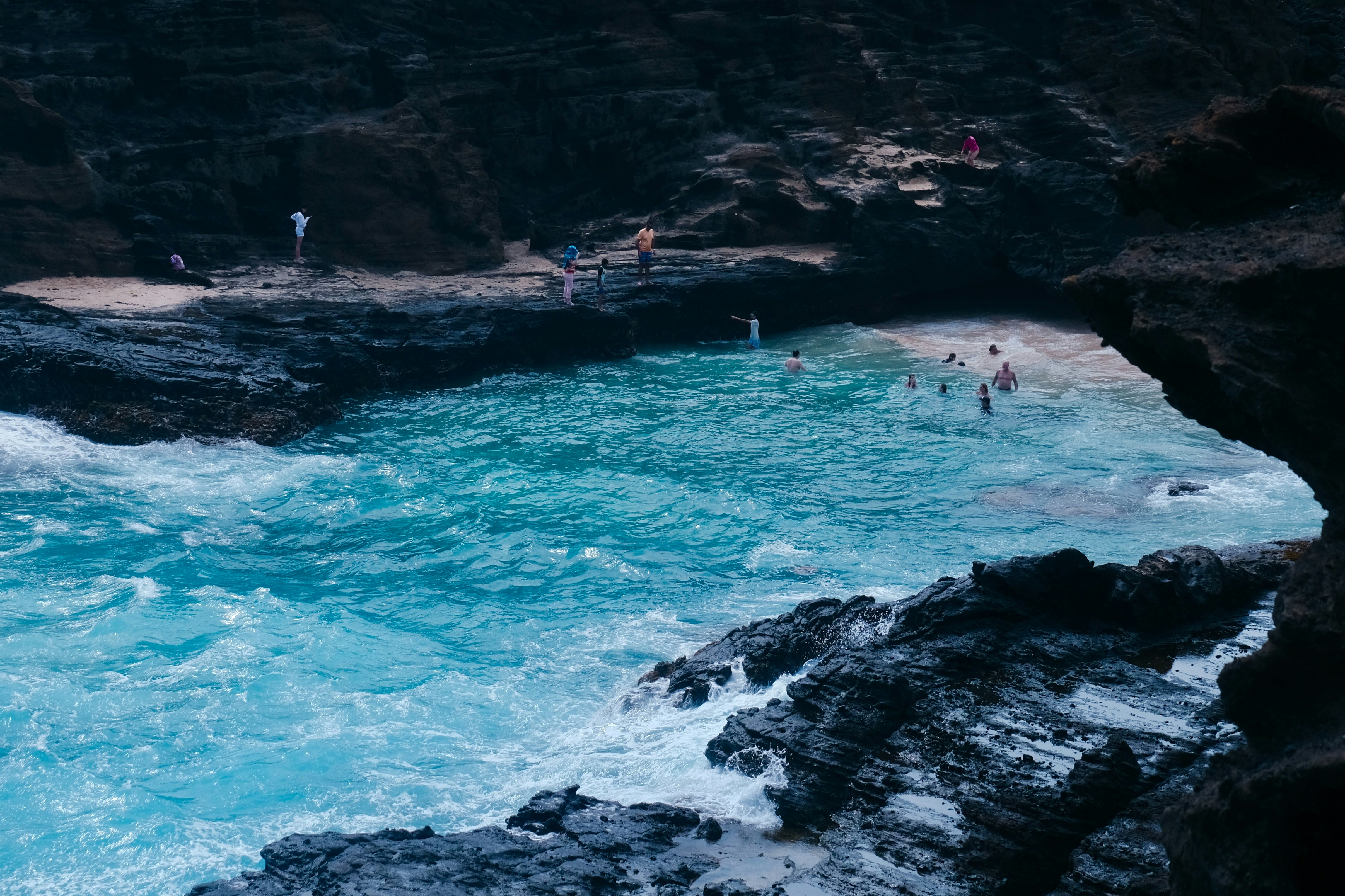 Azure Cove: People Exploring a Turquoise Coastal Pool