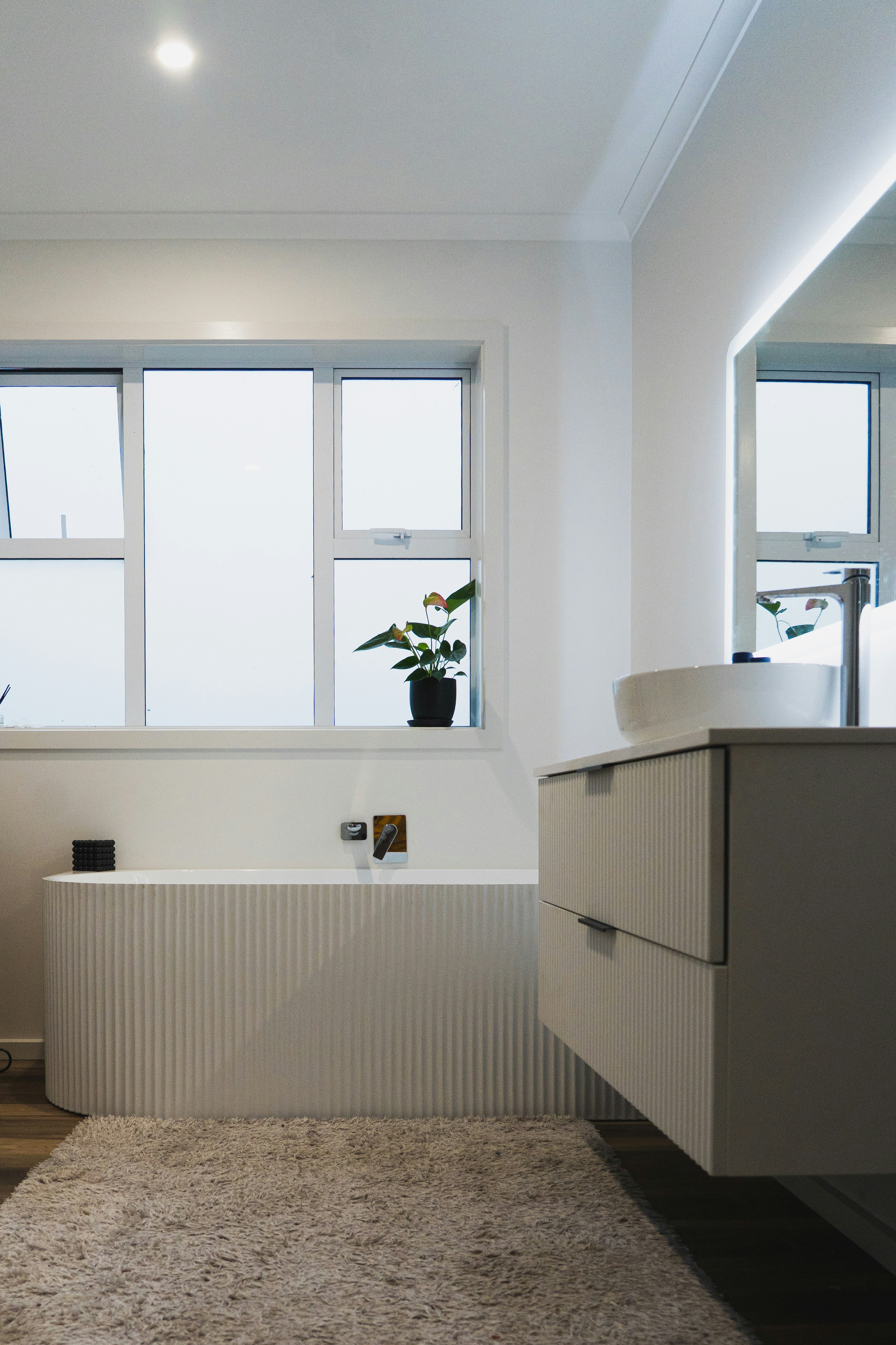 Minimalist bathroom with soft natural light and a single potted plant