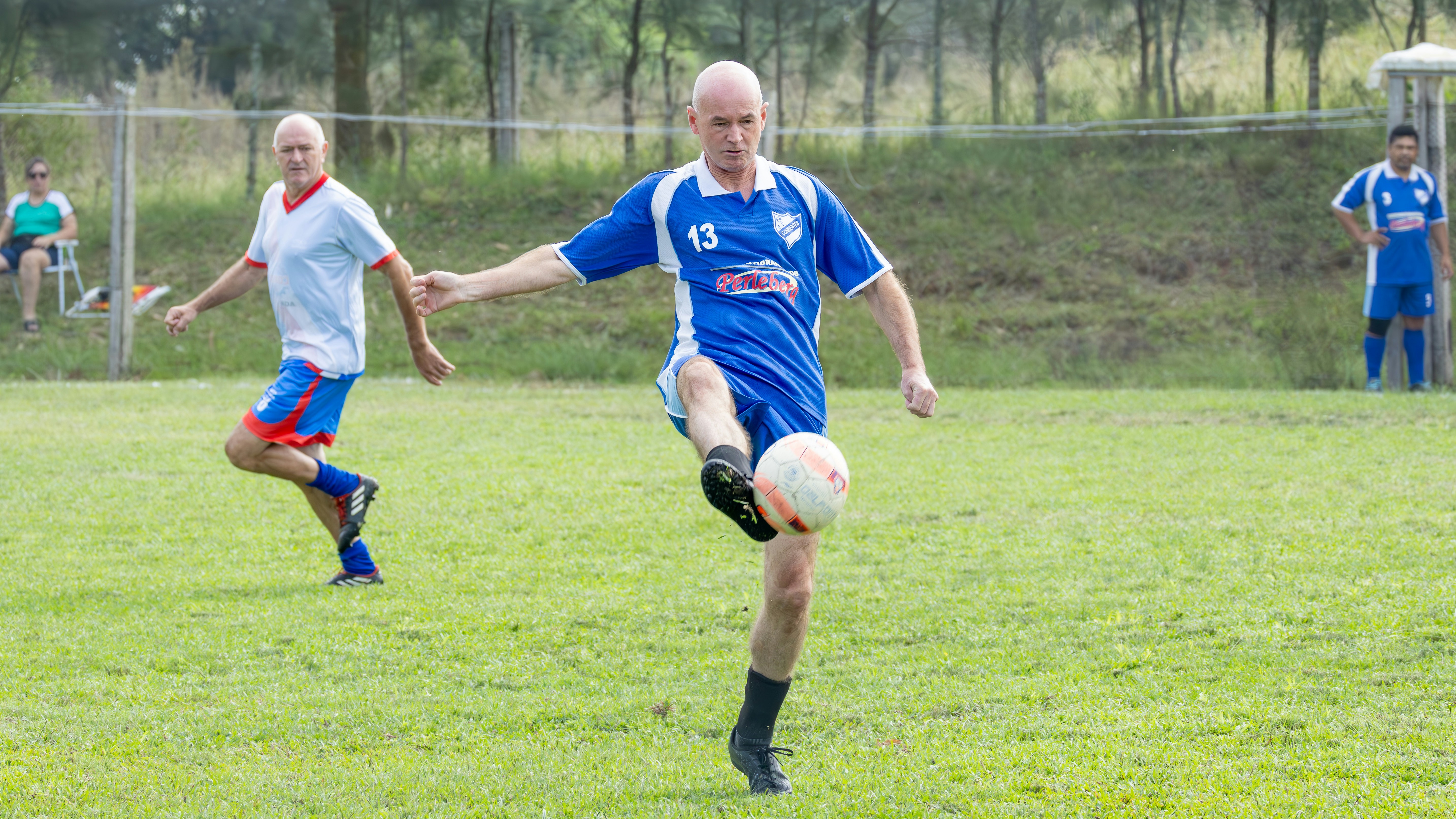 Midfield Moment: The Bald Player Launches a Precise Strike
