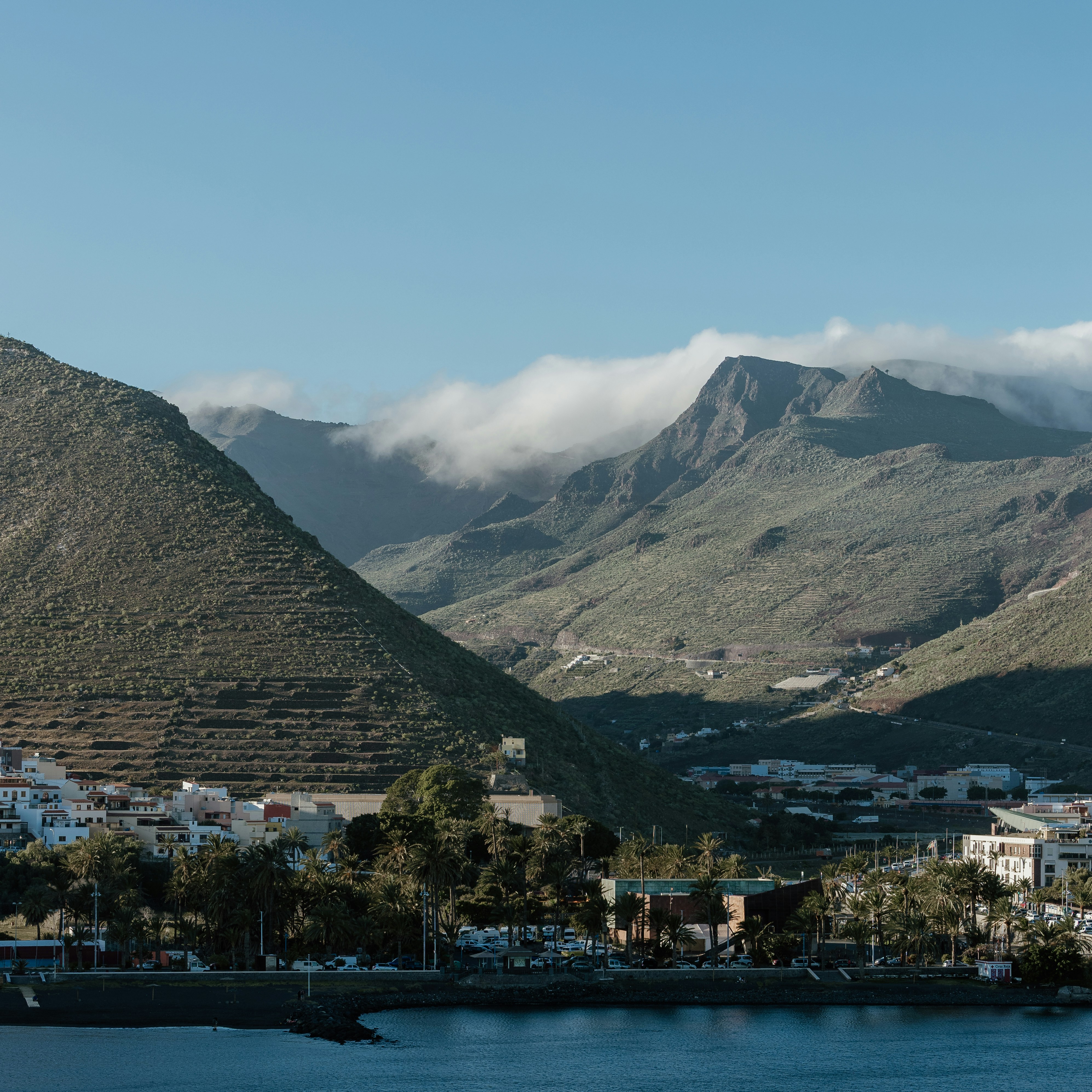 Coastal village at the foot of rugged mountains under a clear blue sky