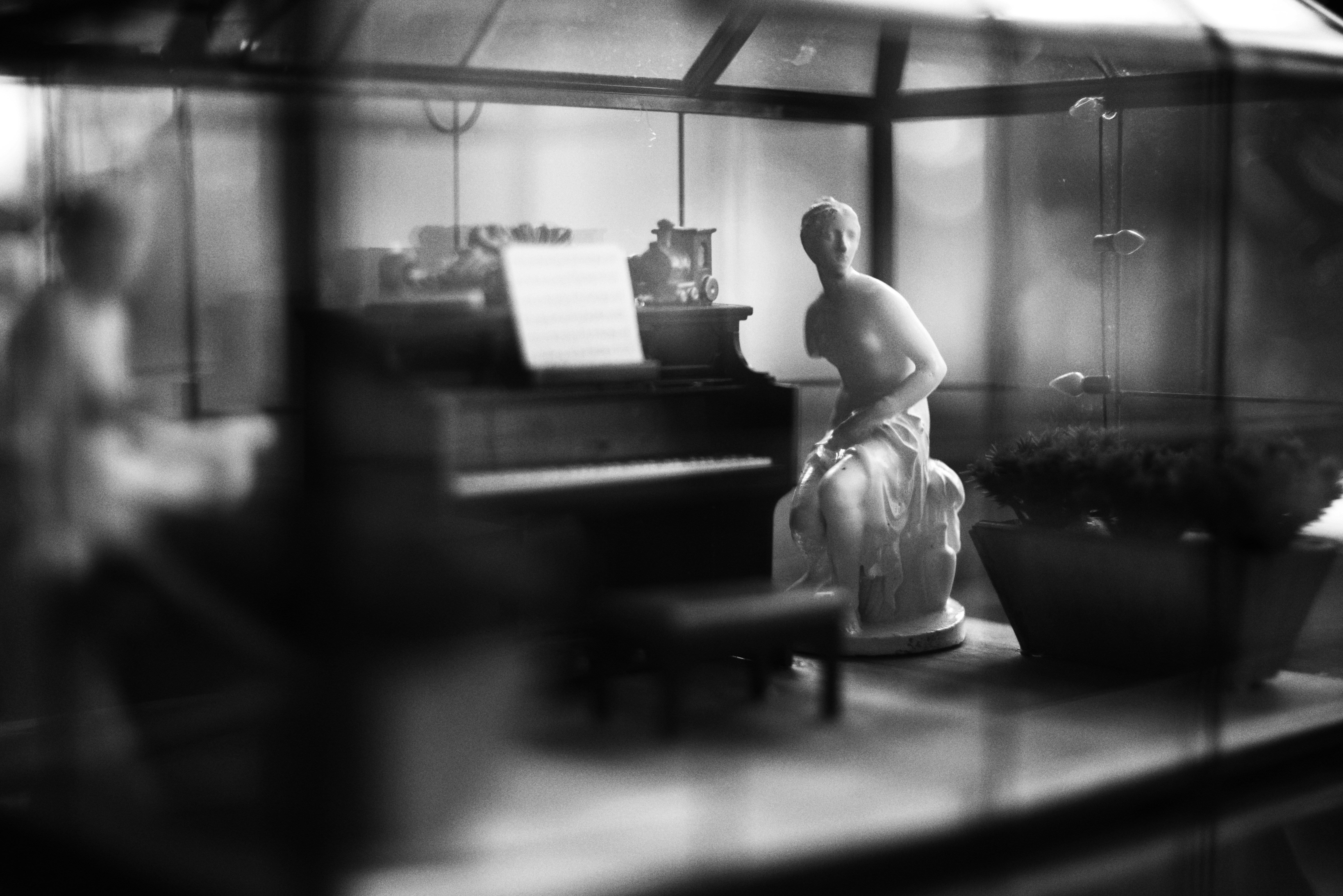 Silent Recital: A porcelain statue beside a softly lit piano