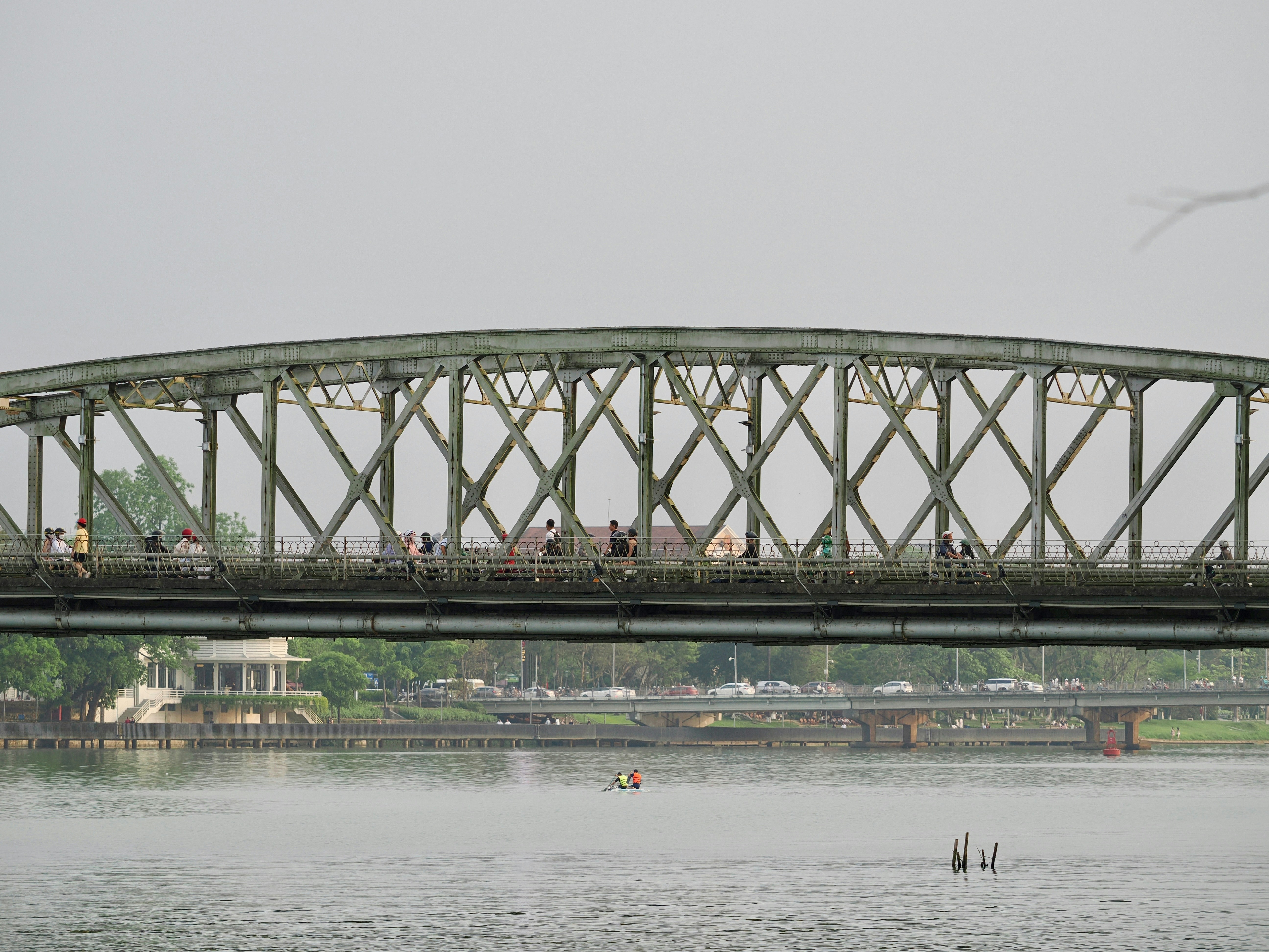 Railway Bridge Over Calm River: People Crossing Toward the City