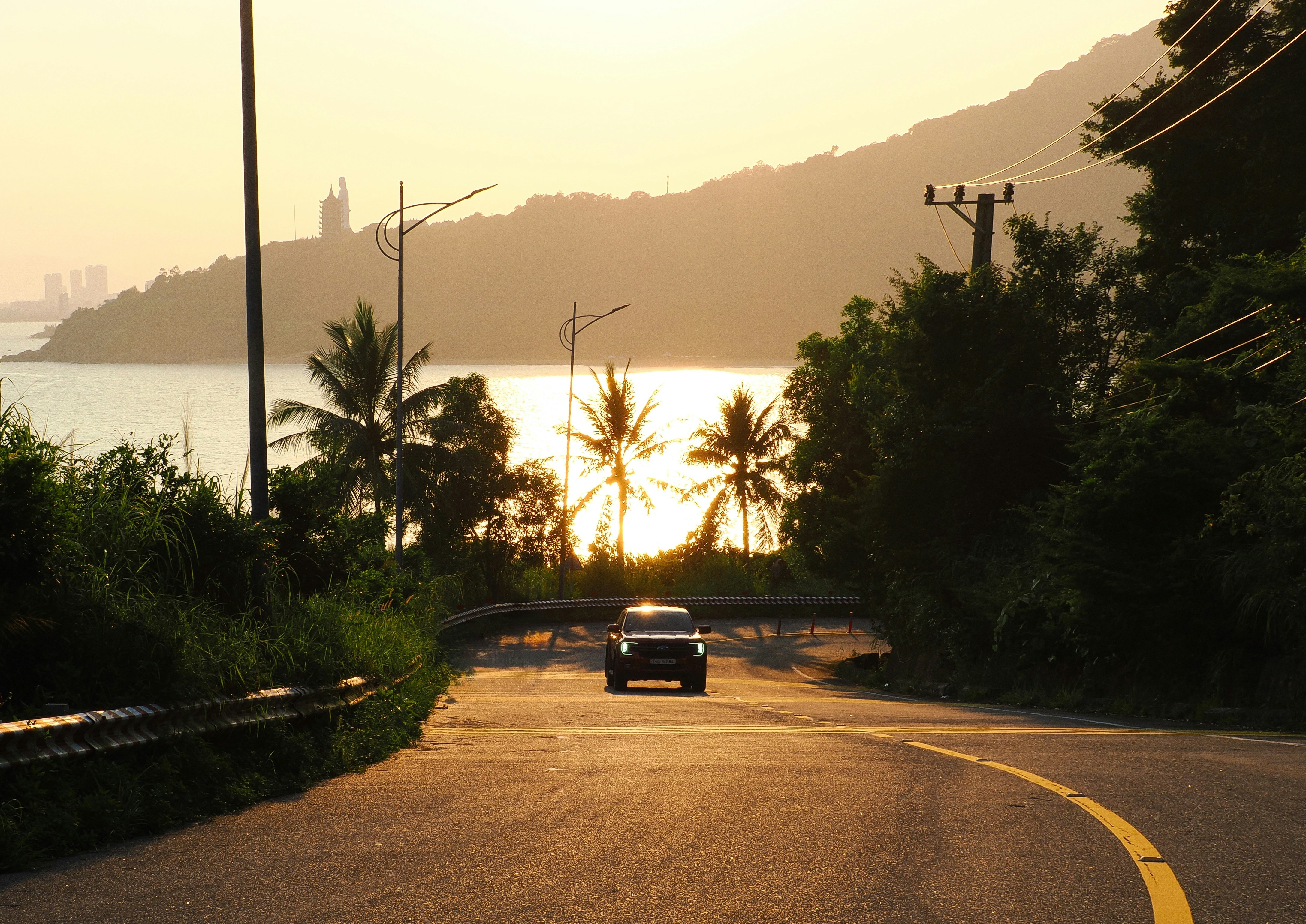 Sunlit Coastal Road: Car Traverses a Quiet Curve Toward the Golden Horizon