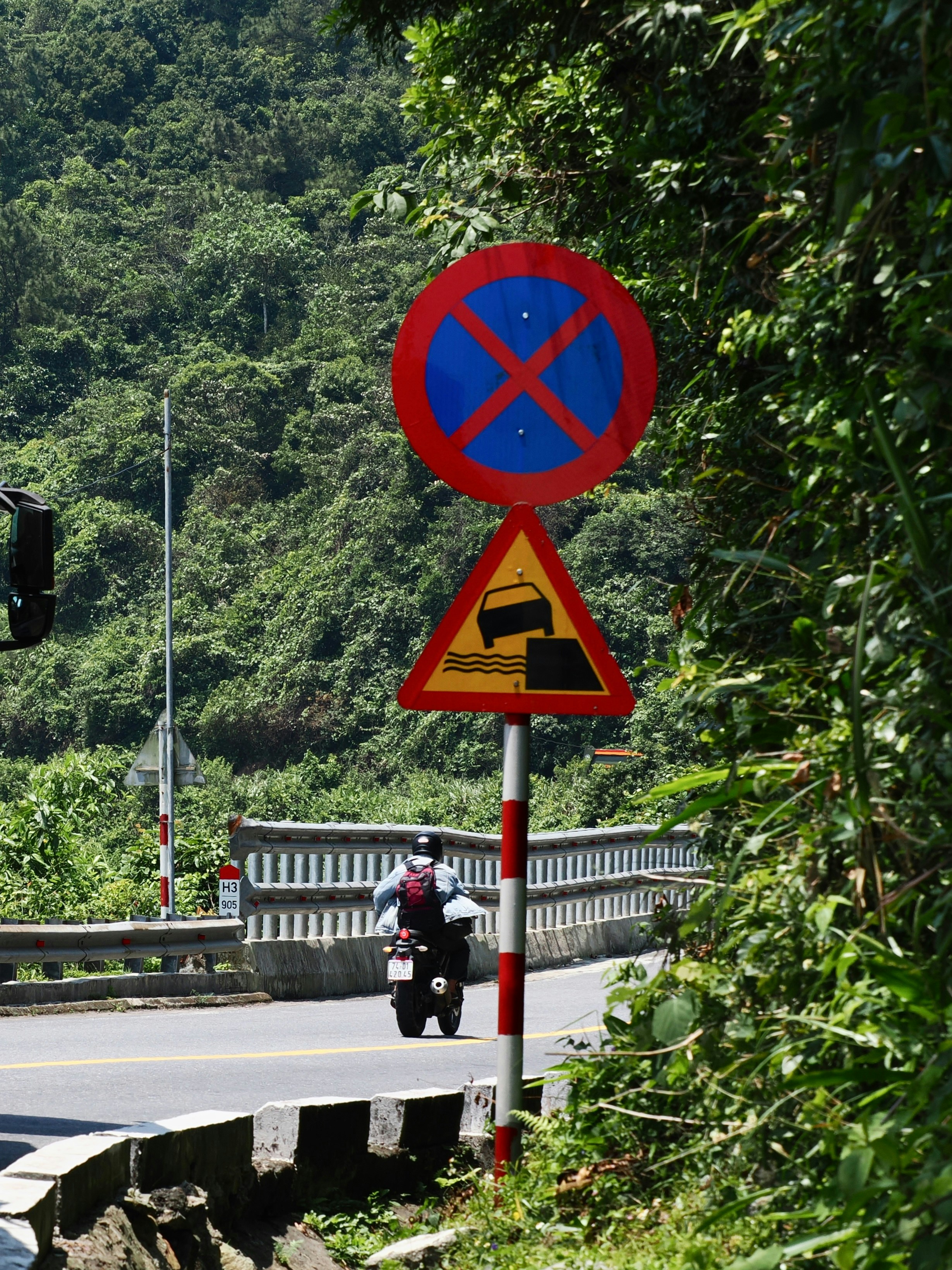 Signpost Sentinel: A Motorcycle Rides Beneath Warning Signals