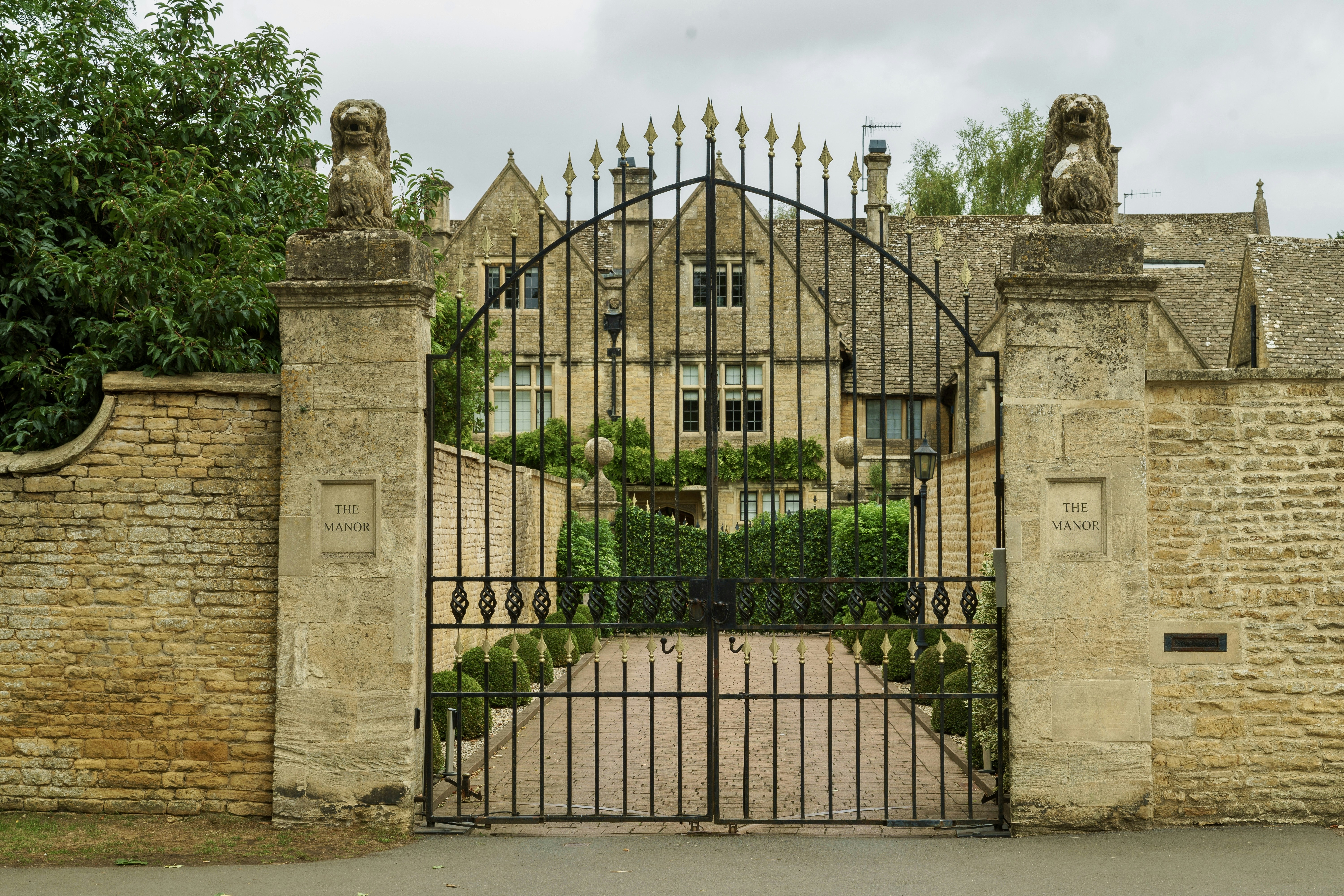 Iron Gate to a Sunlit Estate: A Floral Path Through Historic Walls