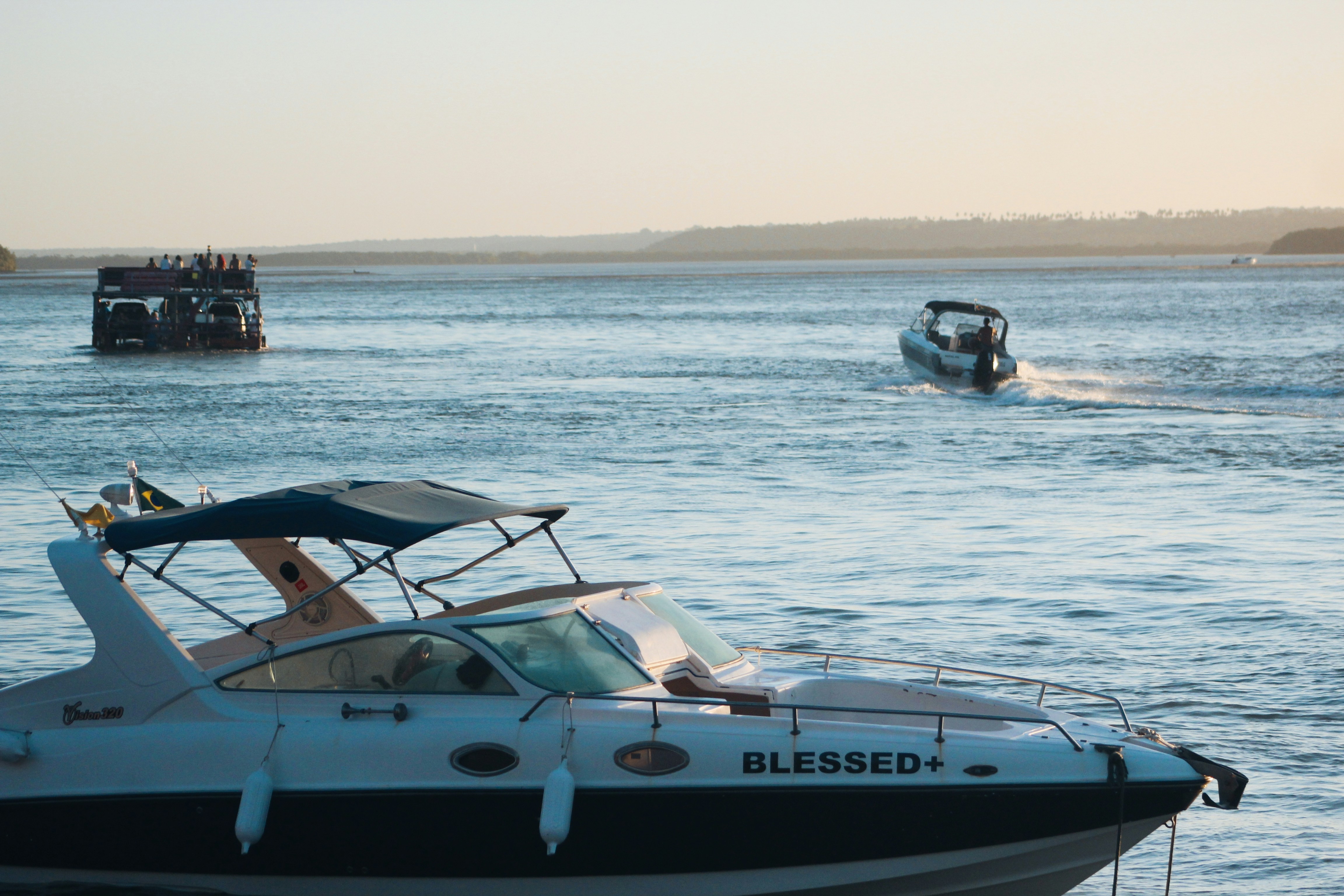 Bayside Wake: A Quiet Moment with a Sunlit Yacht and Backdrop of Calmer Waters