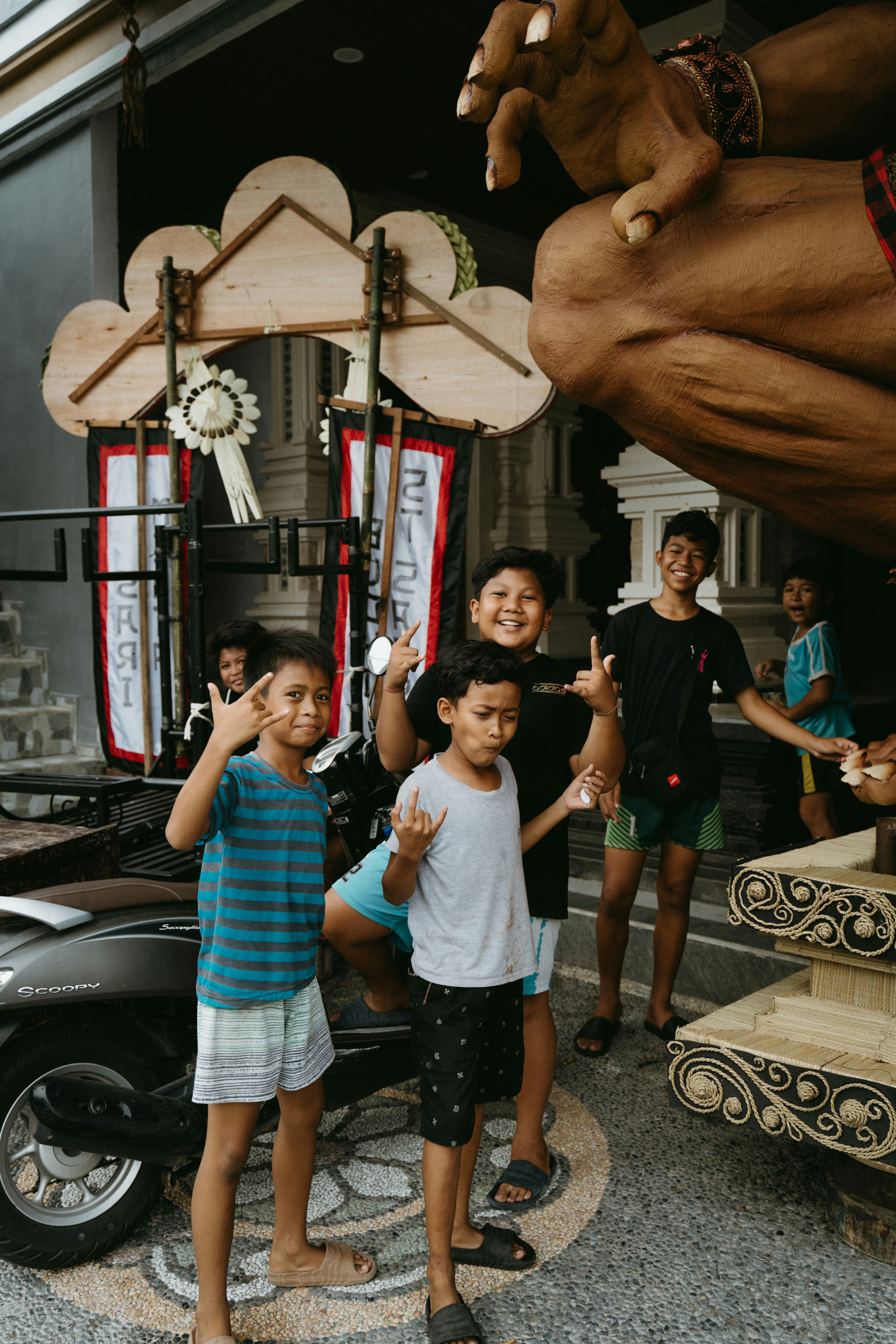 Joyful Croppers: Kids Strike a Playful Pose by a Giant Prayer Hand