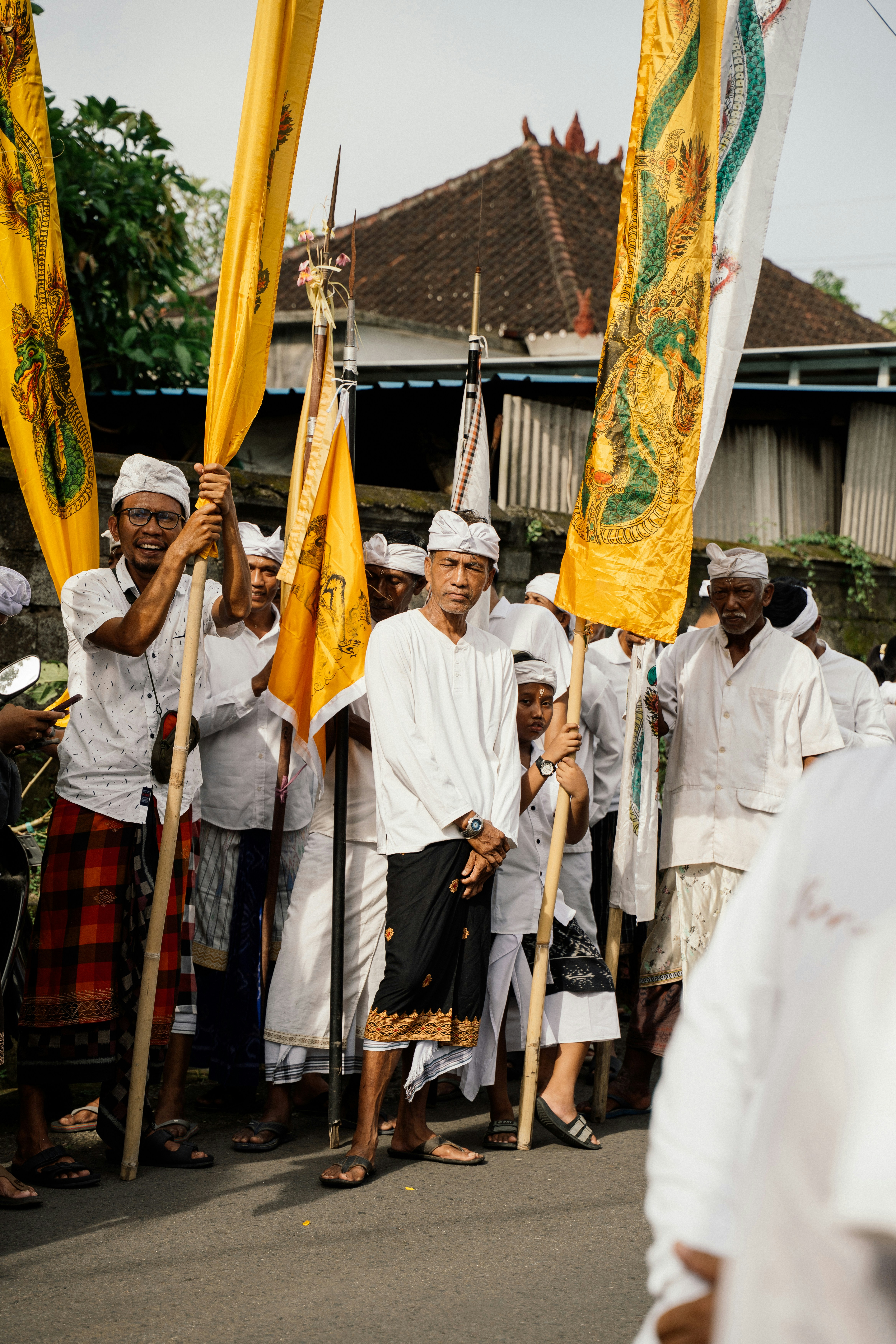 Procession of White-clad Dignitaries with Golden Banners in a Southeast Asian Street