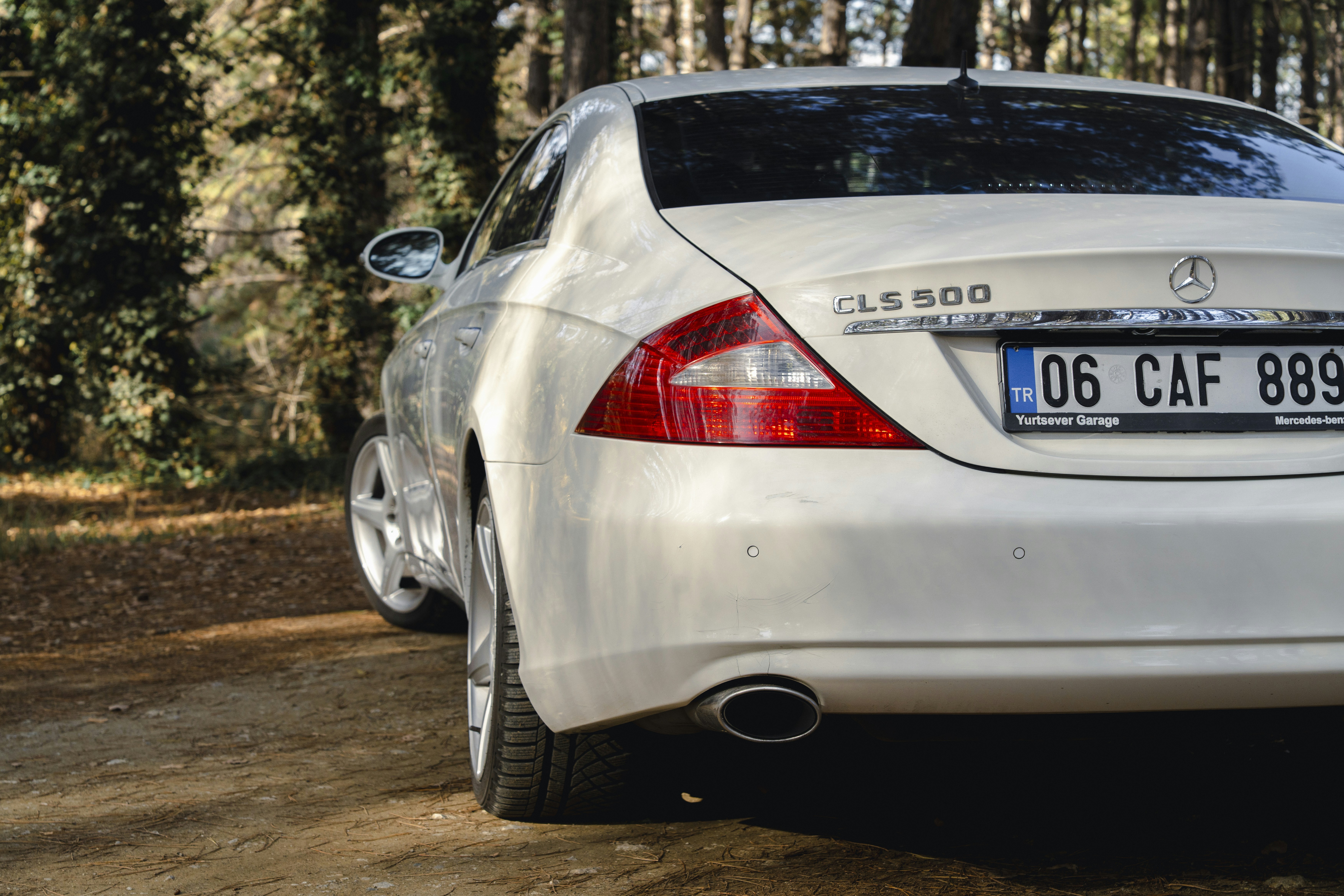 Rear Quarter View of a White Mercedes CLS 500 in a Forest Parking Area