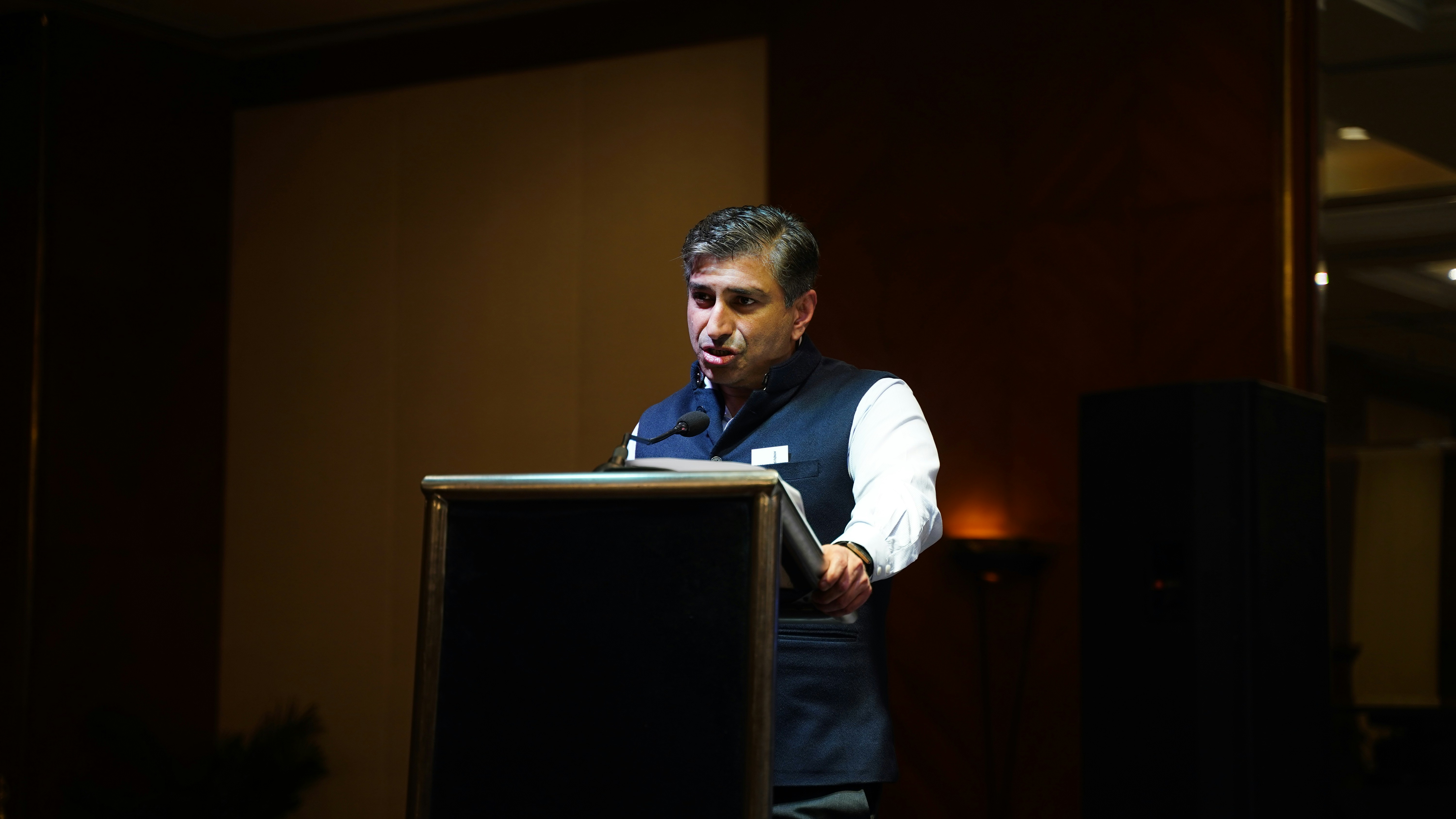Speaker at the Podium: Quiet Confidence Under Warm Glow