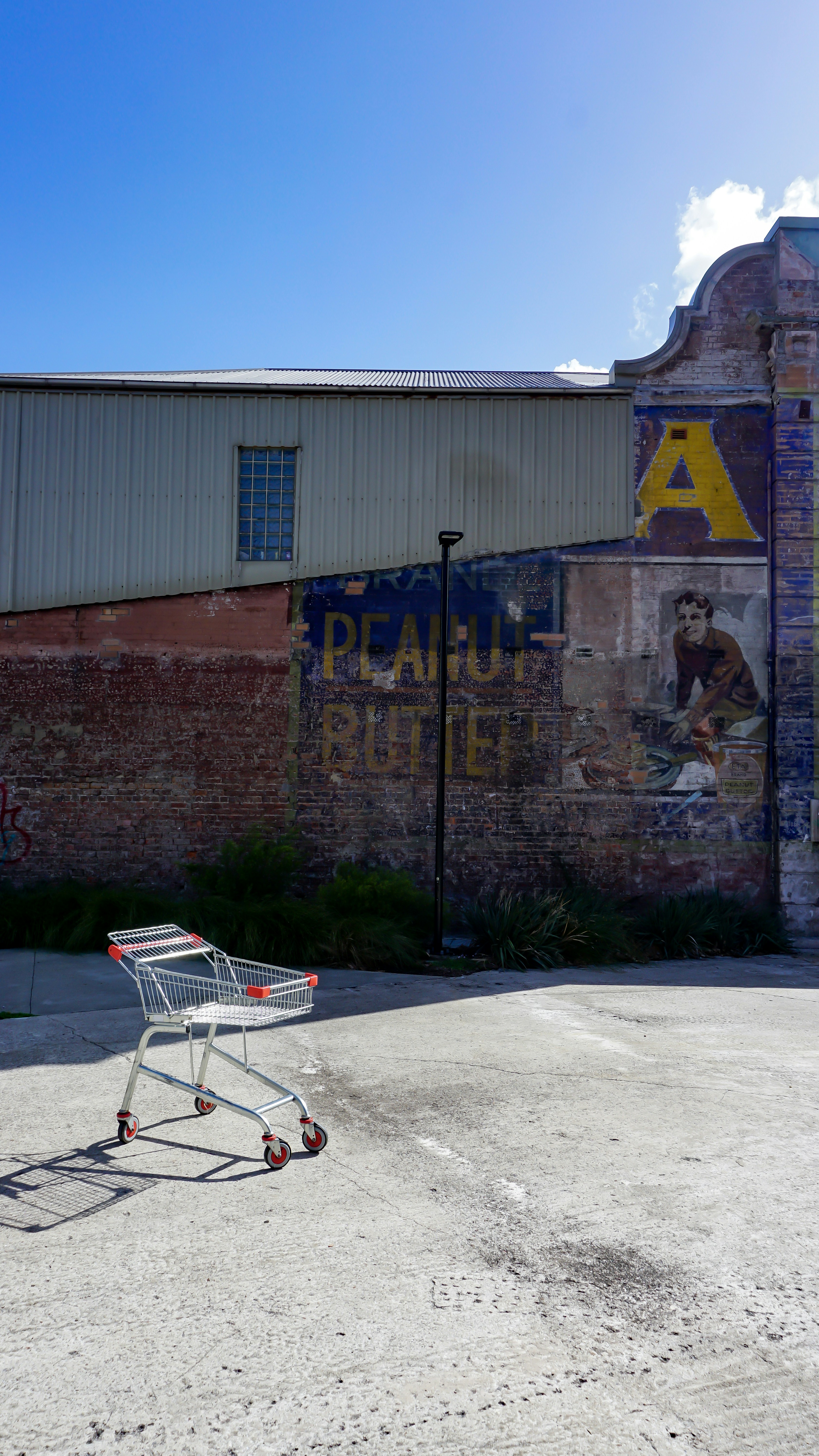 Deserted lot with a lone shopping cart under a weathered brick wall