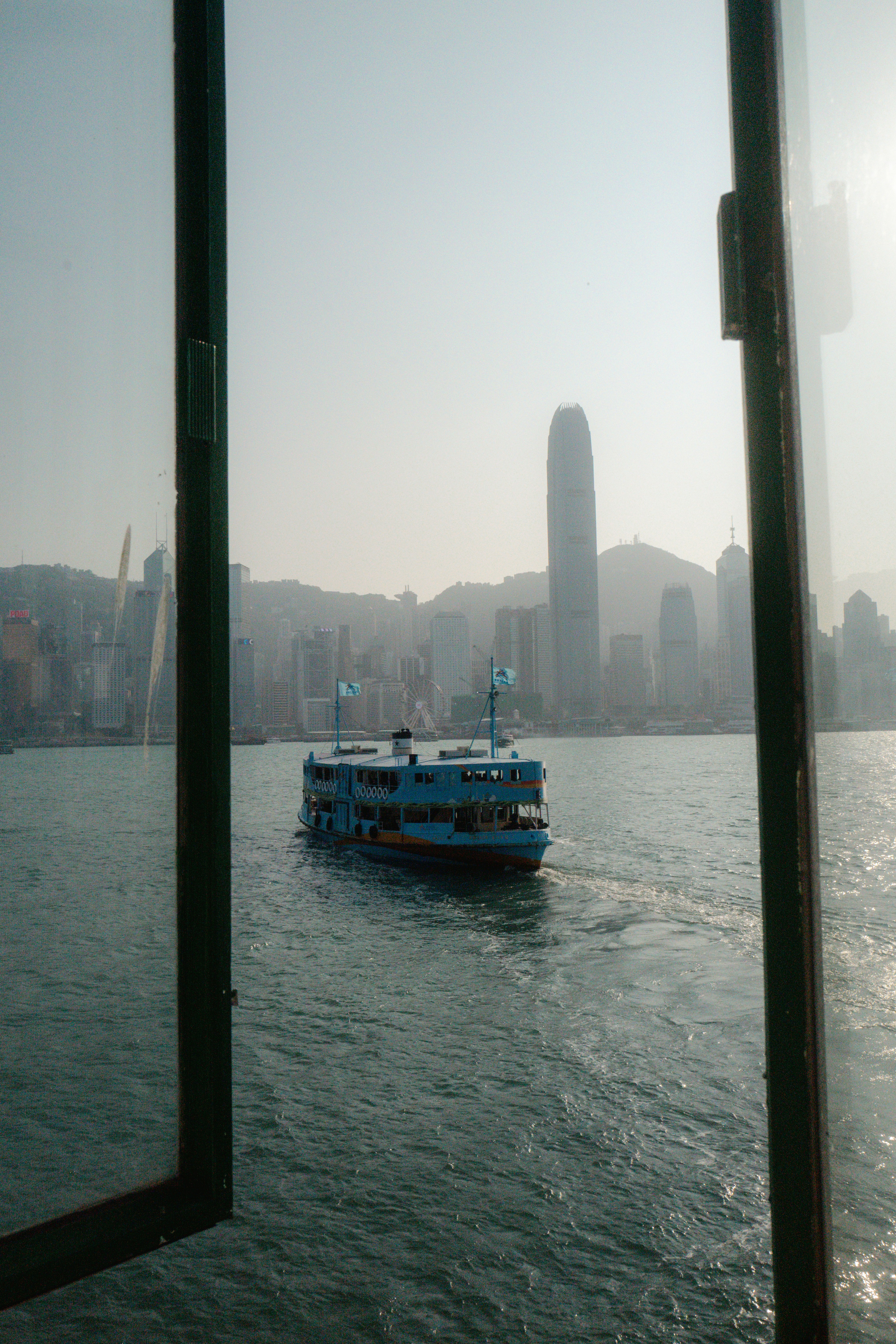 Blue Ferry Cutting Through Hong Kong’s Morning Light