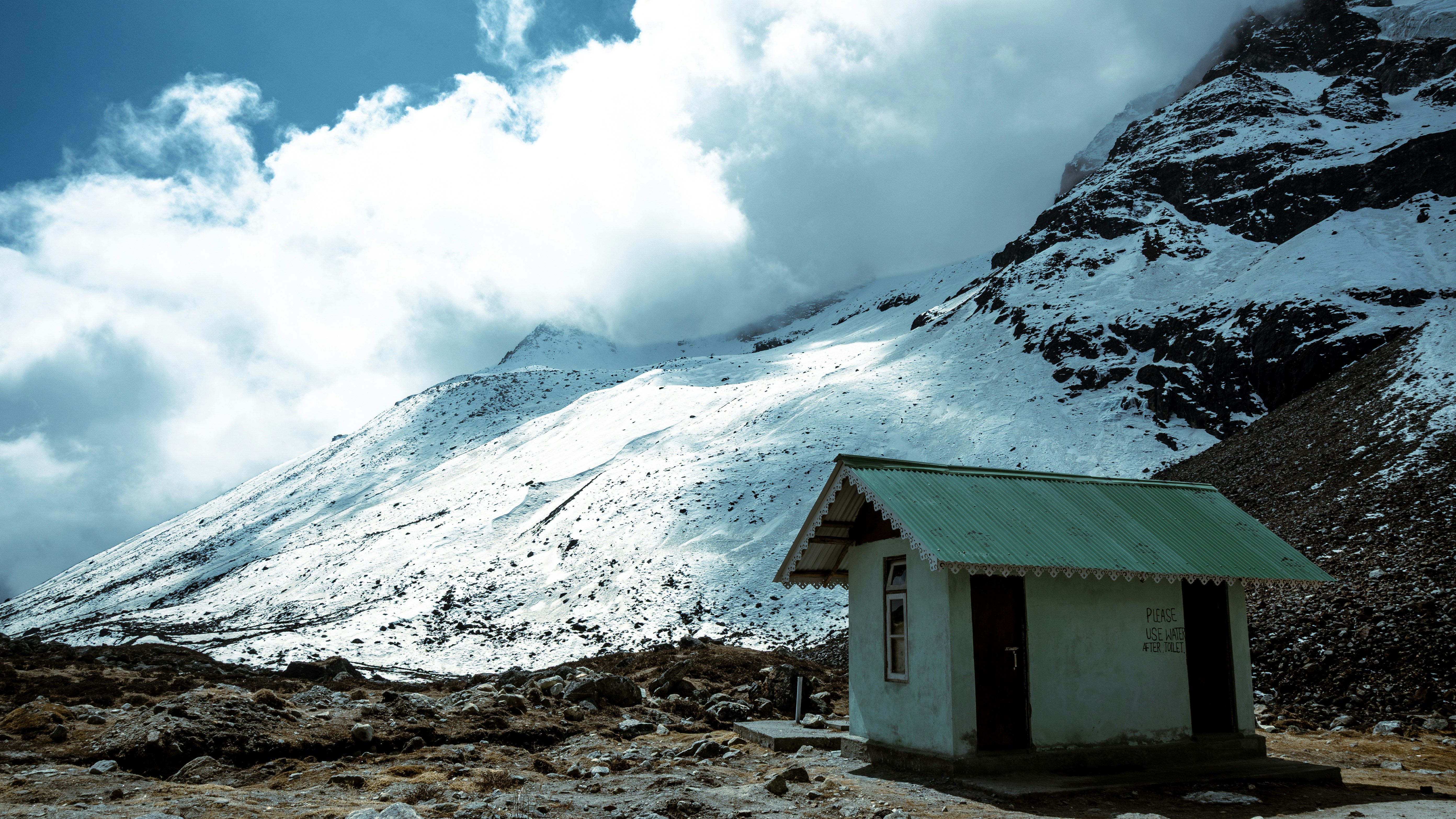 Green-roofed Alpine Shelter Nestled against Snow-dusted Peaks
