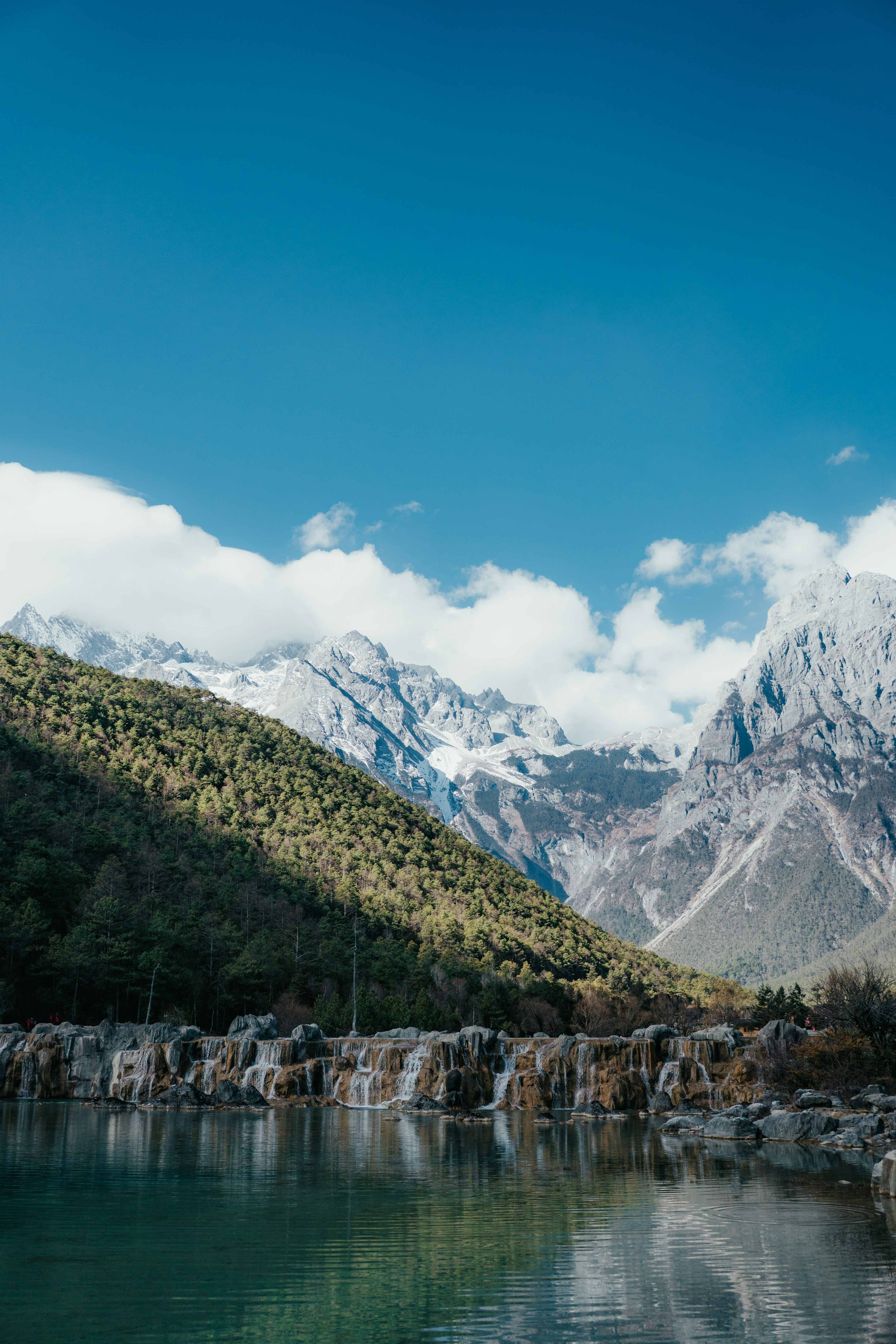 Valley Between Peaks: A Fresh Cascading Lake Under a Clear Sky
