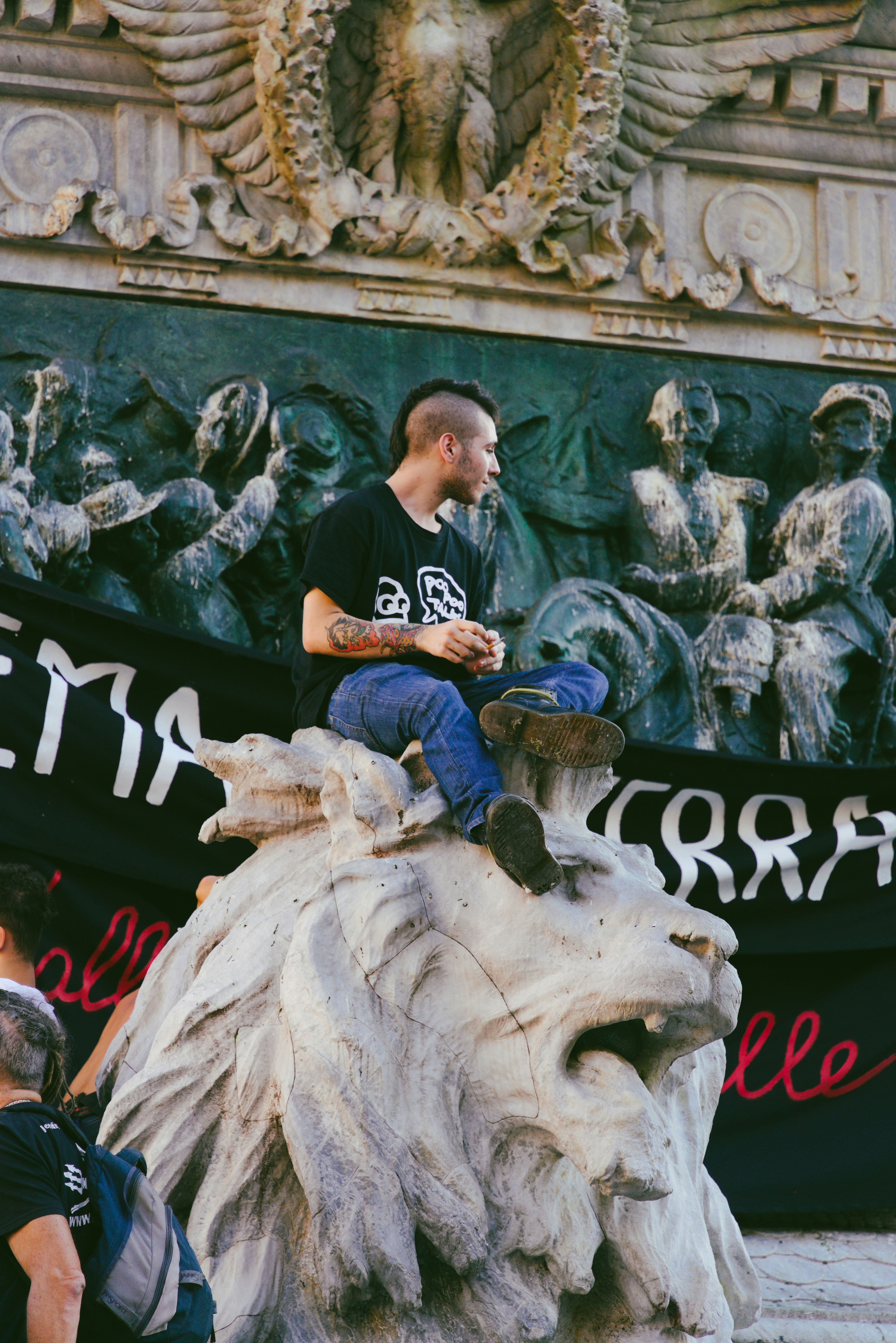 Sitting on a Stone Lion: A Man with Tattoos Overlooking a Historical Relief