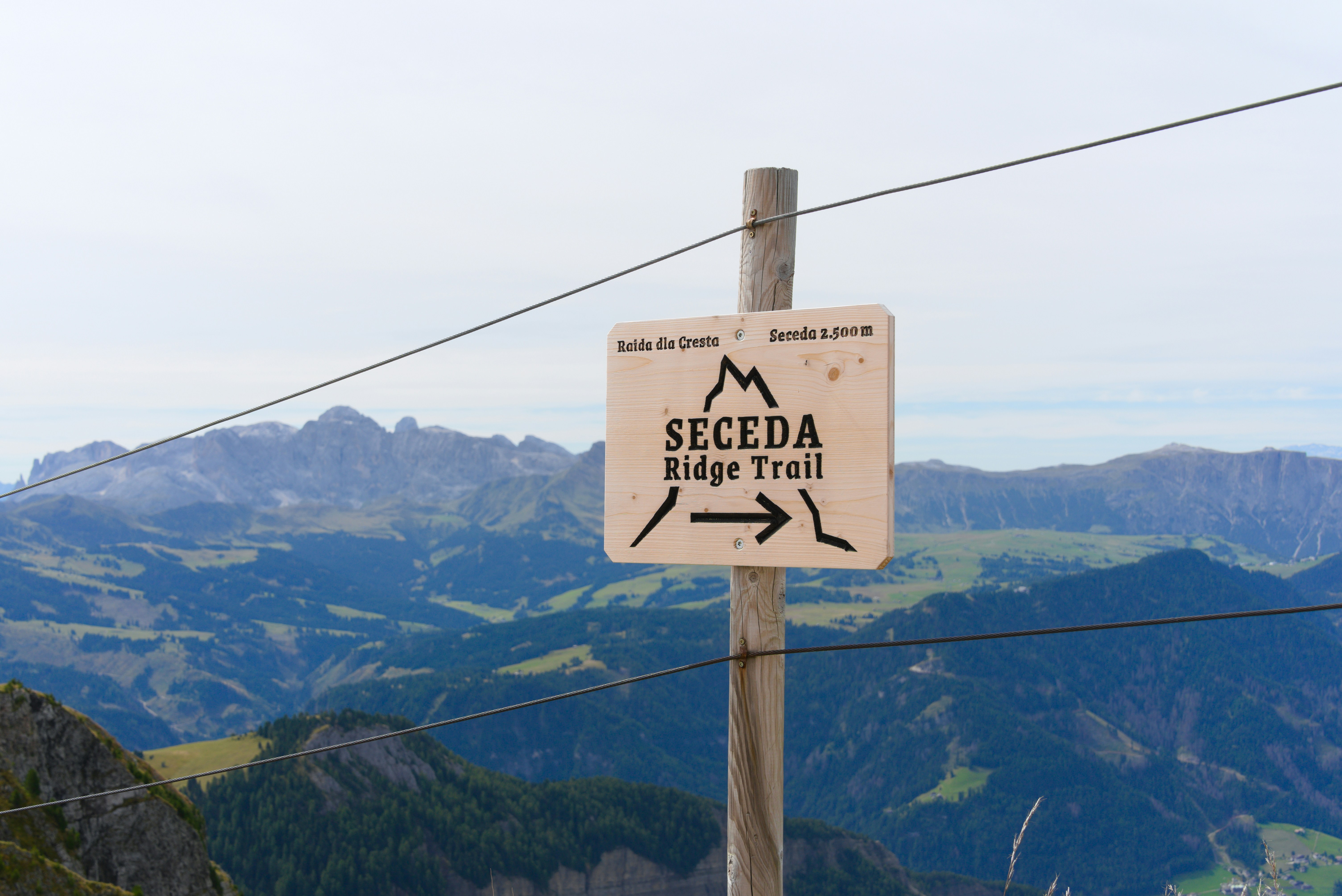 Signpost on the Ridge: Seceda Trail Overlooking Alpine Valleys
