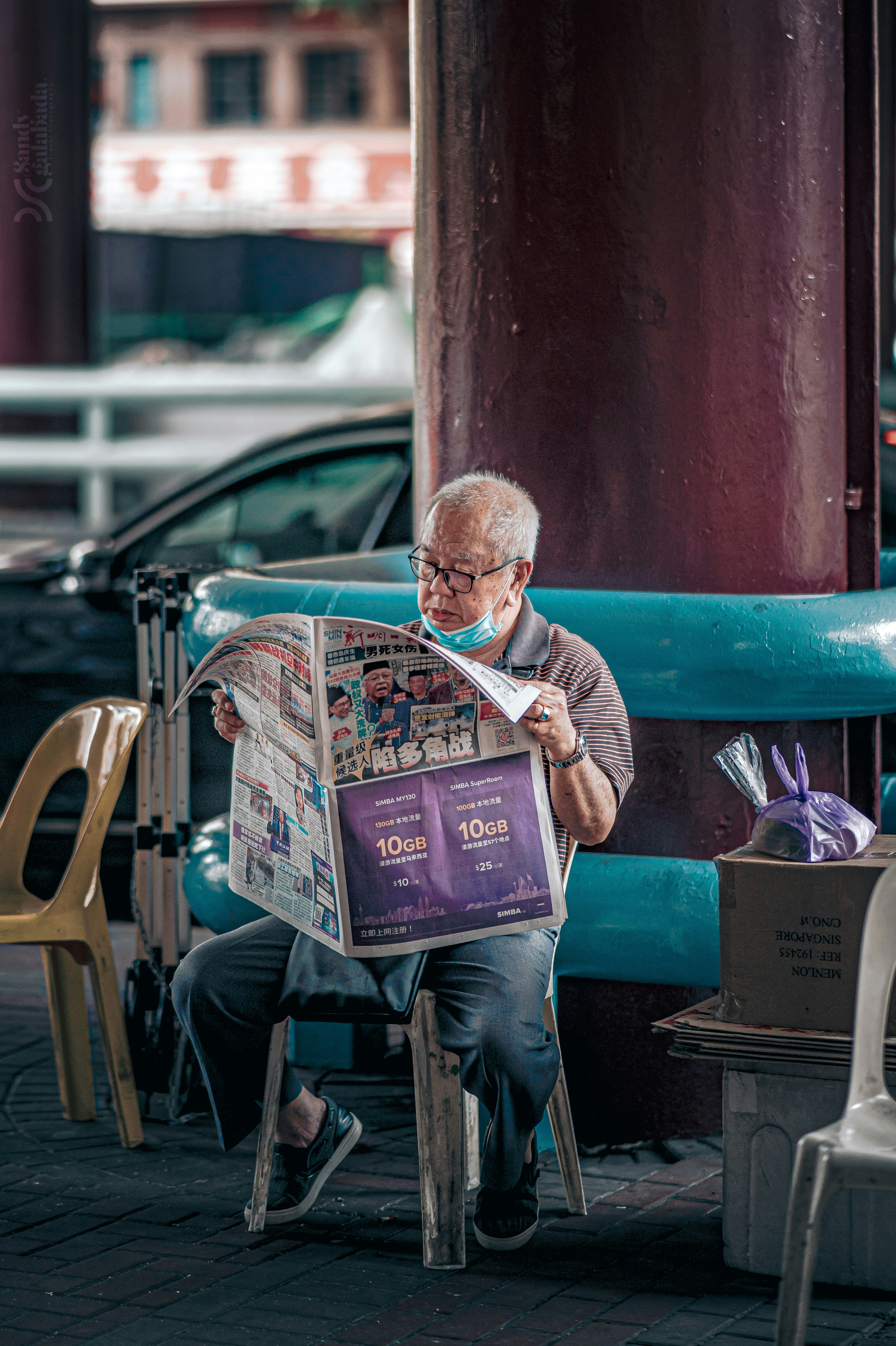 A Quiet Moment Under the Pillar: Newspaper Reader in a Street Nook