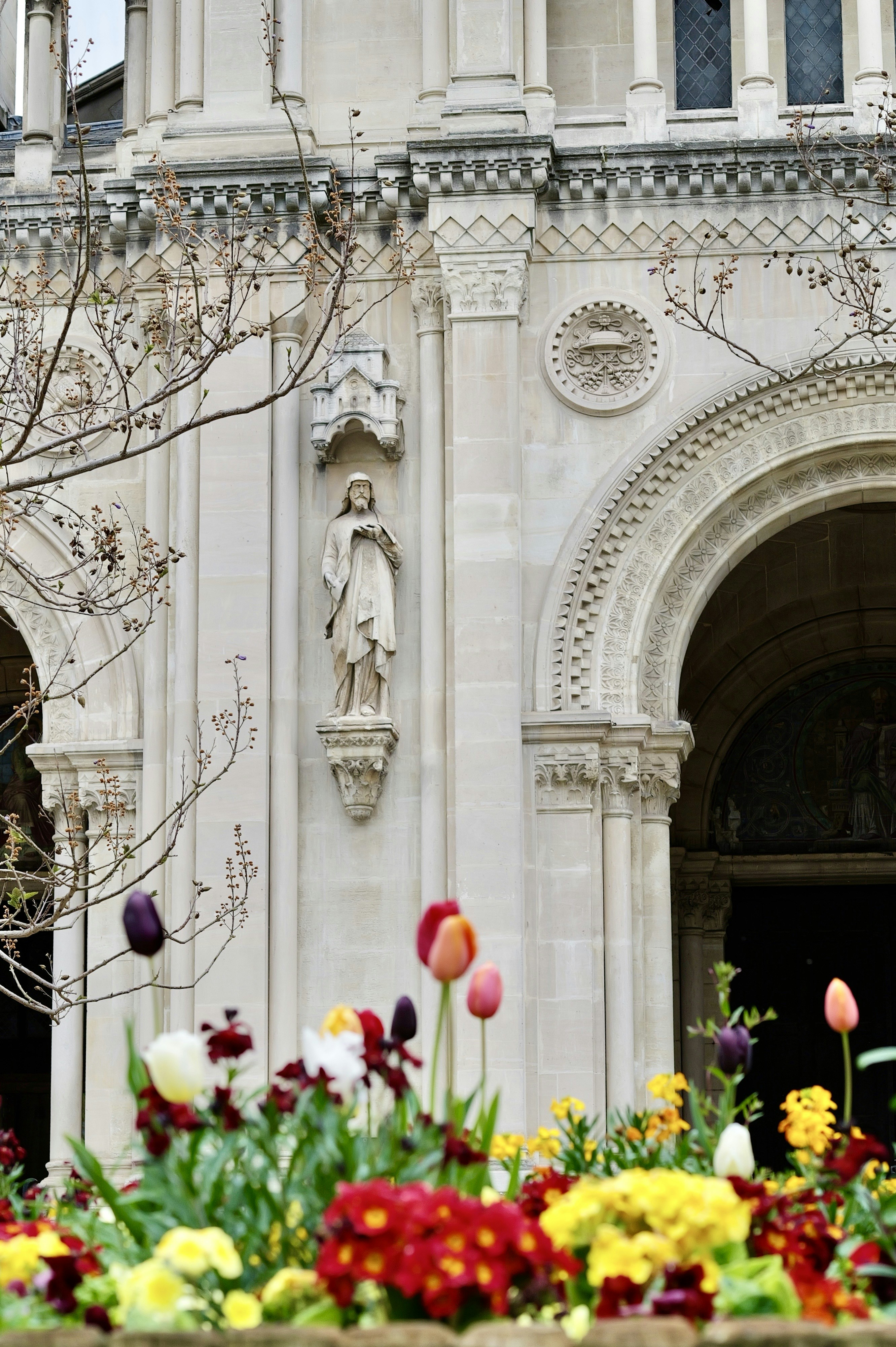 Stone Facade with Garden Bed: A Quiet Cathedral Entrance Framed by Spring Blooms