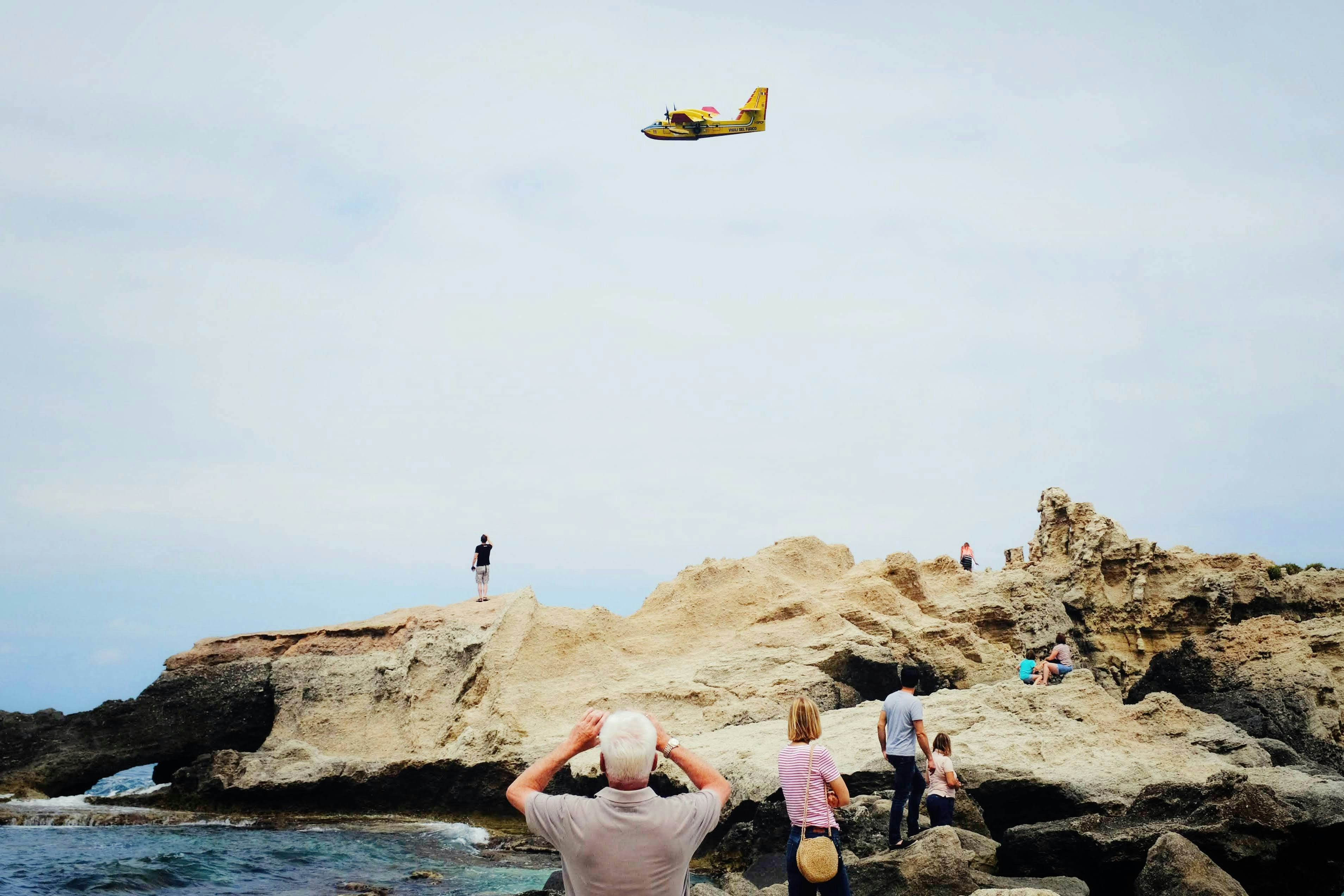 Lone Flyer Over Sea Cliff: A Yellow Plane Above a Quiet Shoreline
