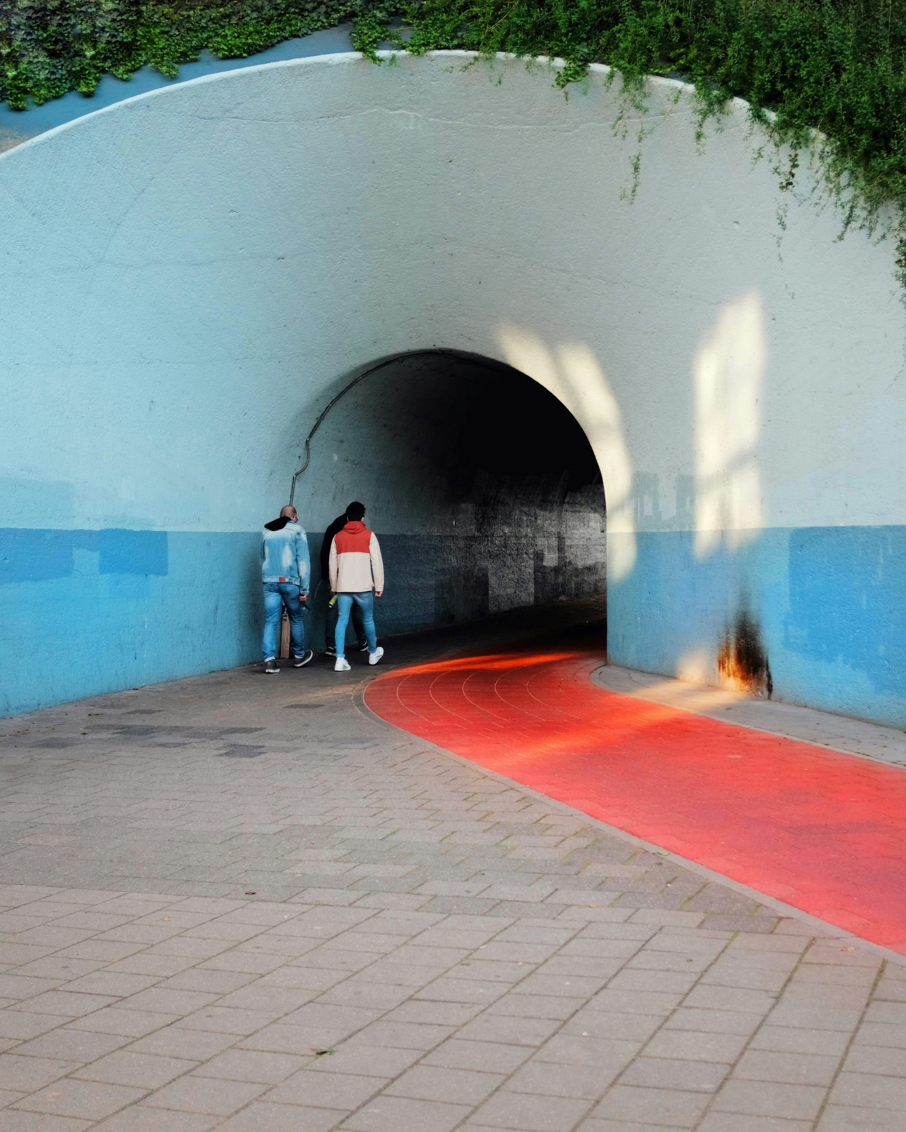 Curved Tunnel Gateway: Two Passersby at the Red Carpet of Light