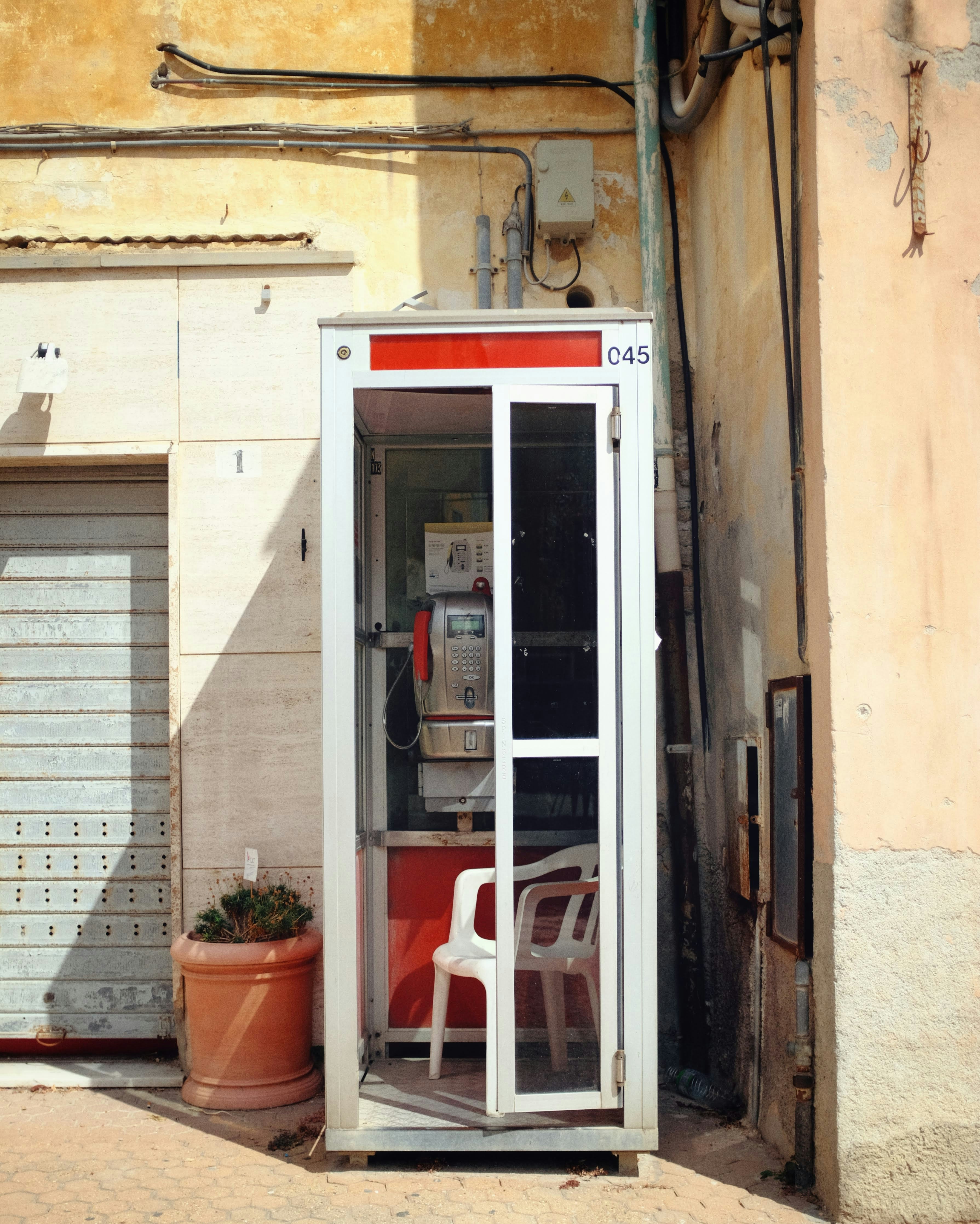 Phone Booth in a Sunlit Mediterranean Alley