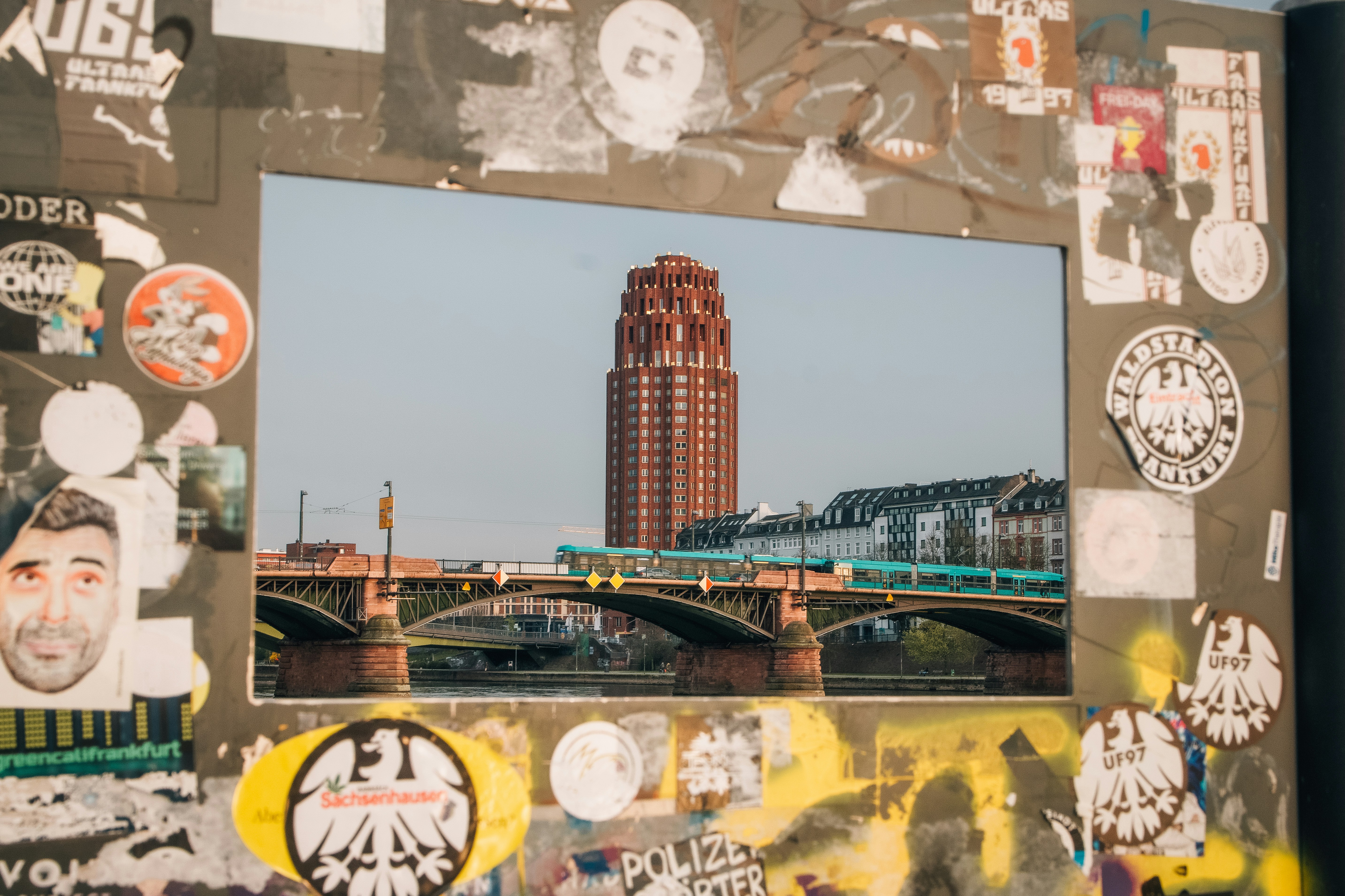Stark skyscraper rising behind a grafitti-strewn wall and bridge