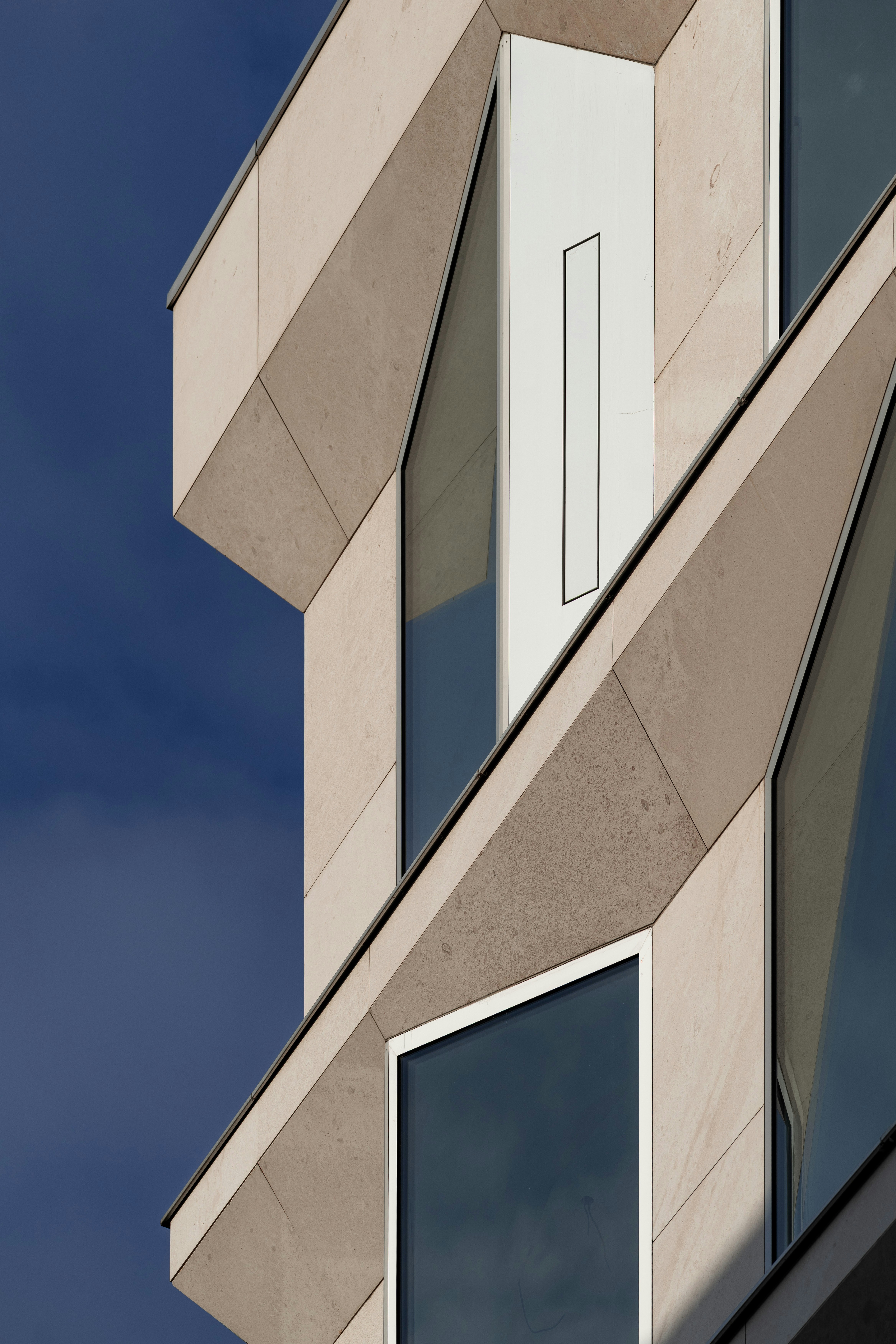 Architectural Angles: diagonal planes illuminate a modern beige-clad facade