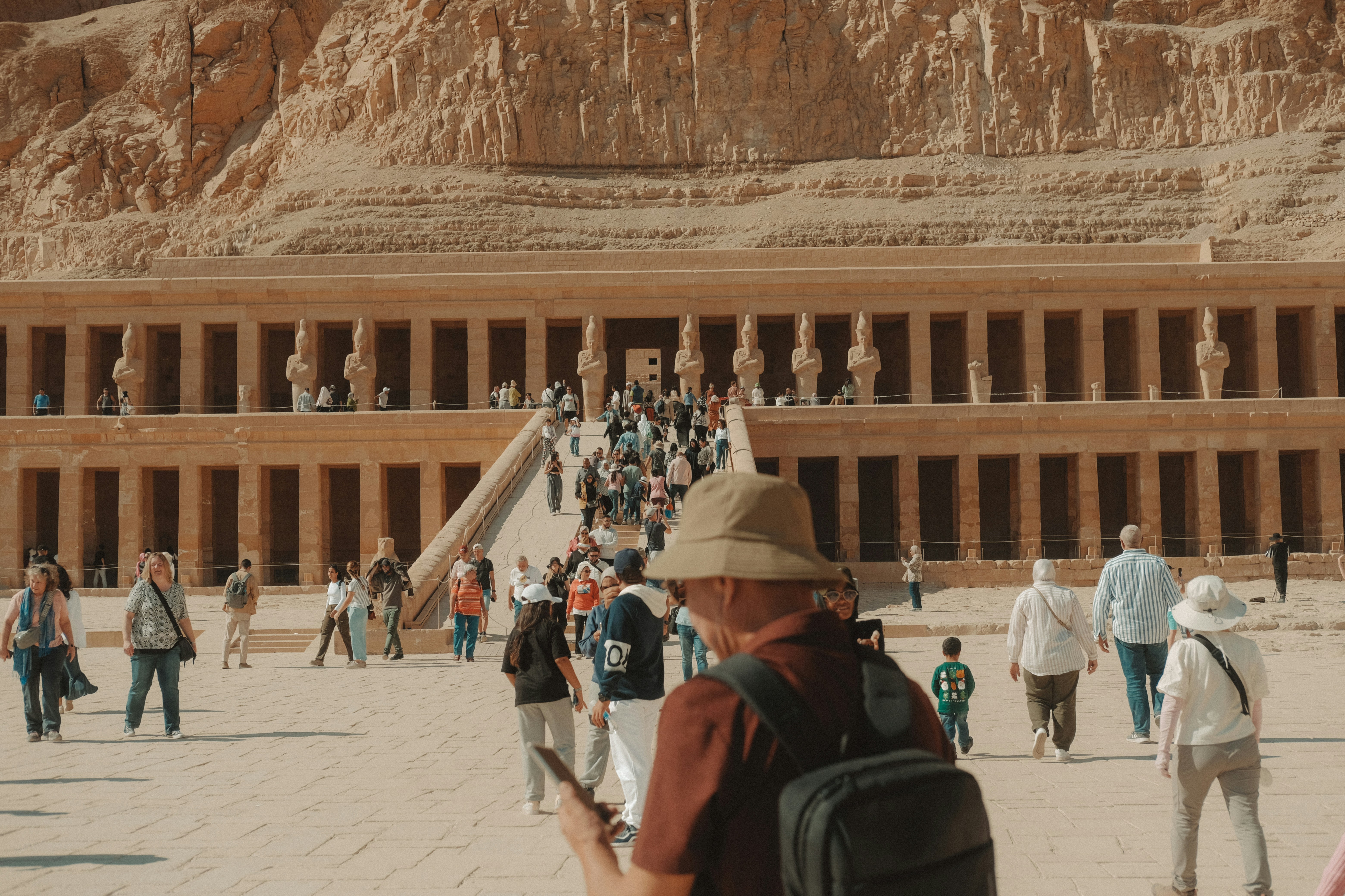 Travelers Entering the Cliffs: A Desert Temple Corridor