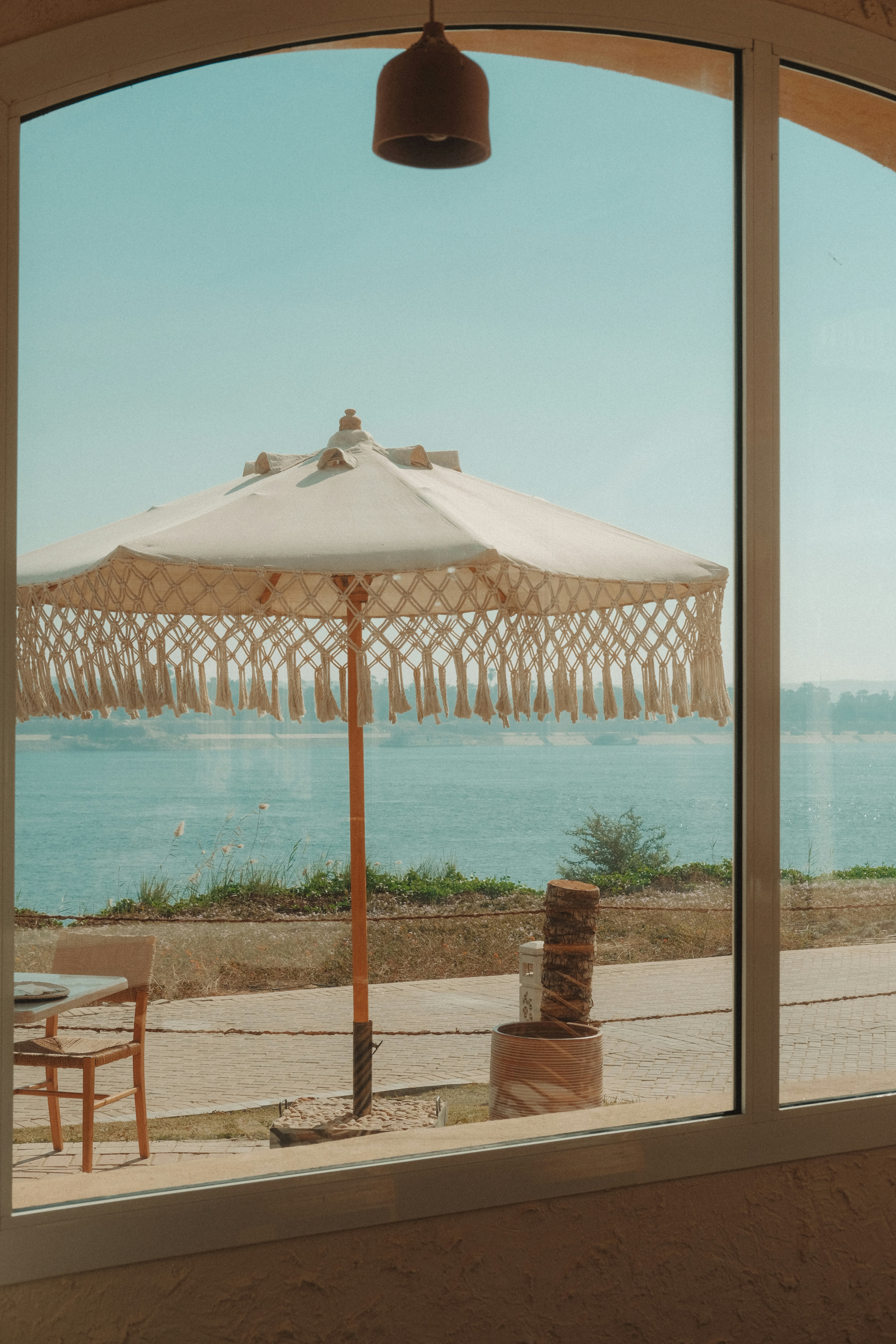 Sea View Through a Framing Window with a Fringed Umbrella