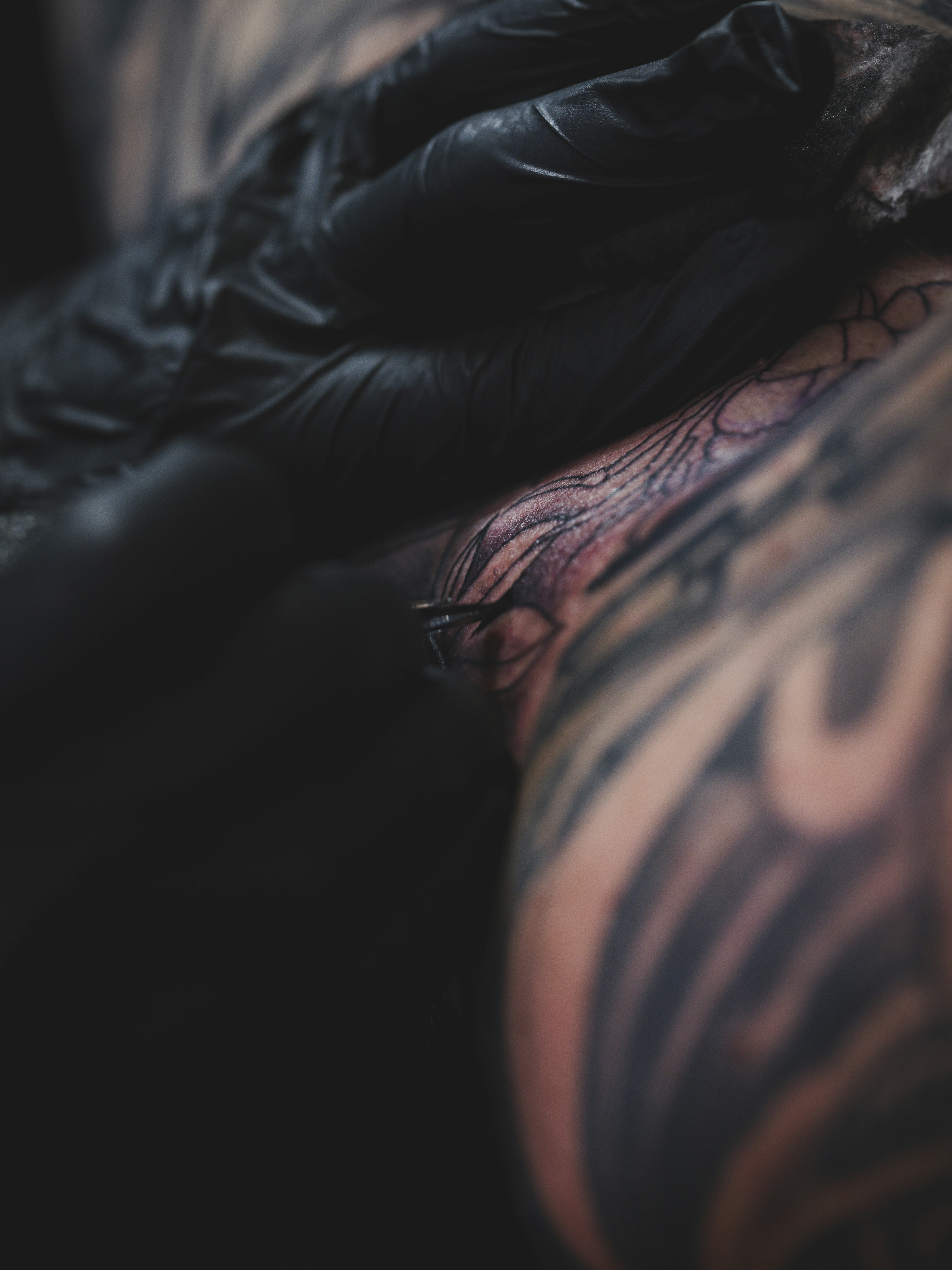 Tattooed Arm Under Gloved Hand: Shaded Portrait of Ink and Skin
