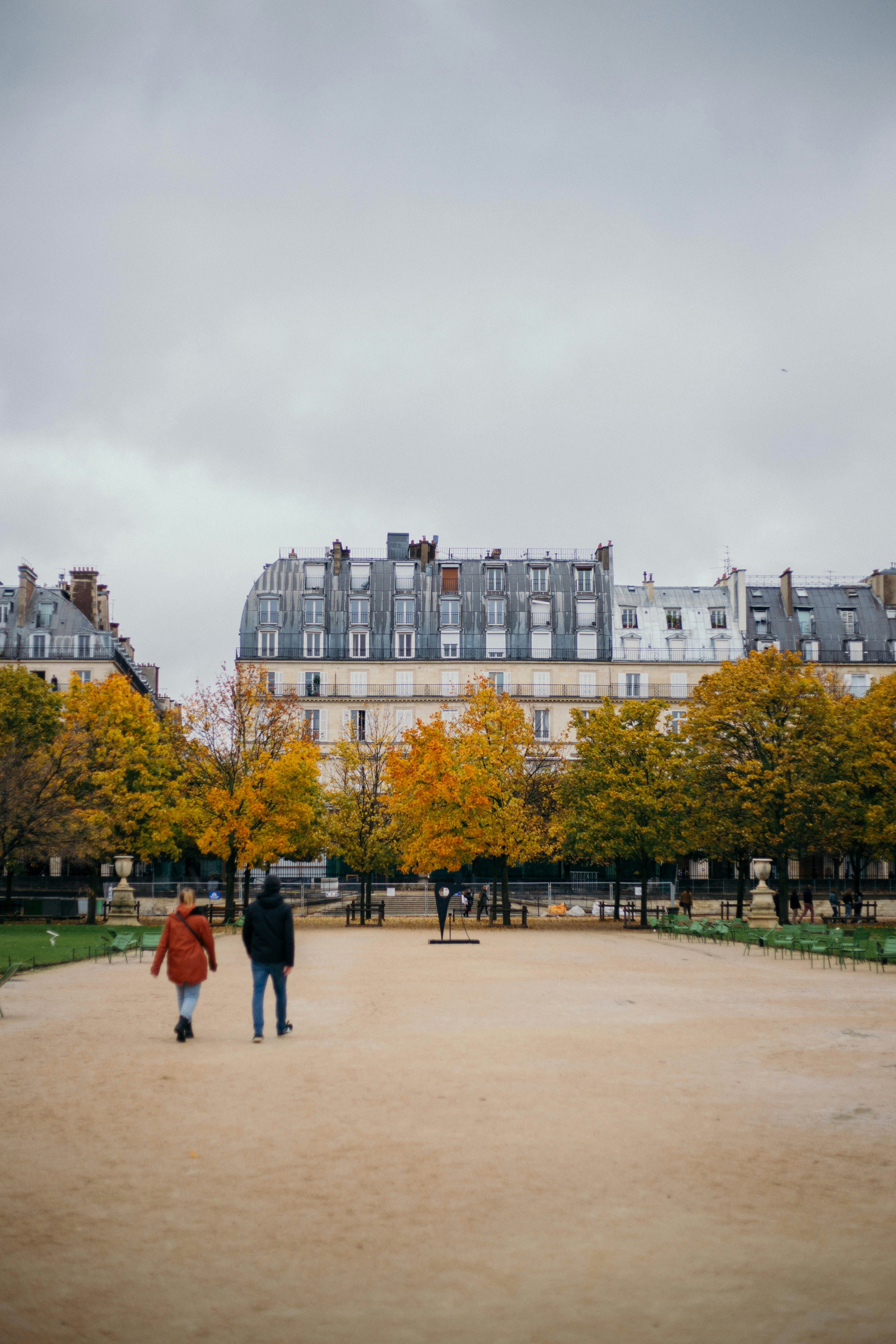 Autumn Avenue: couple strolling toward a Parisian courtyard beneath gilded trees