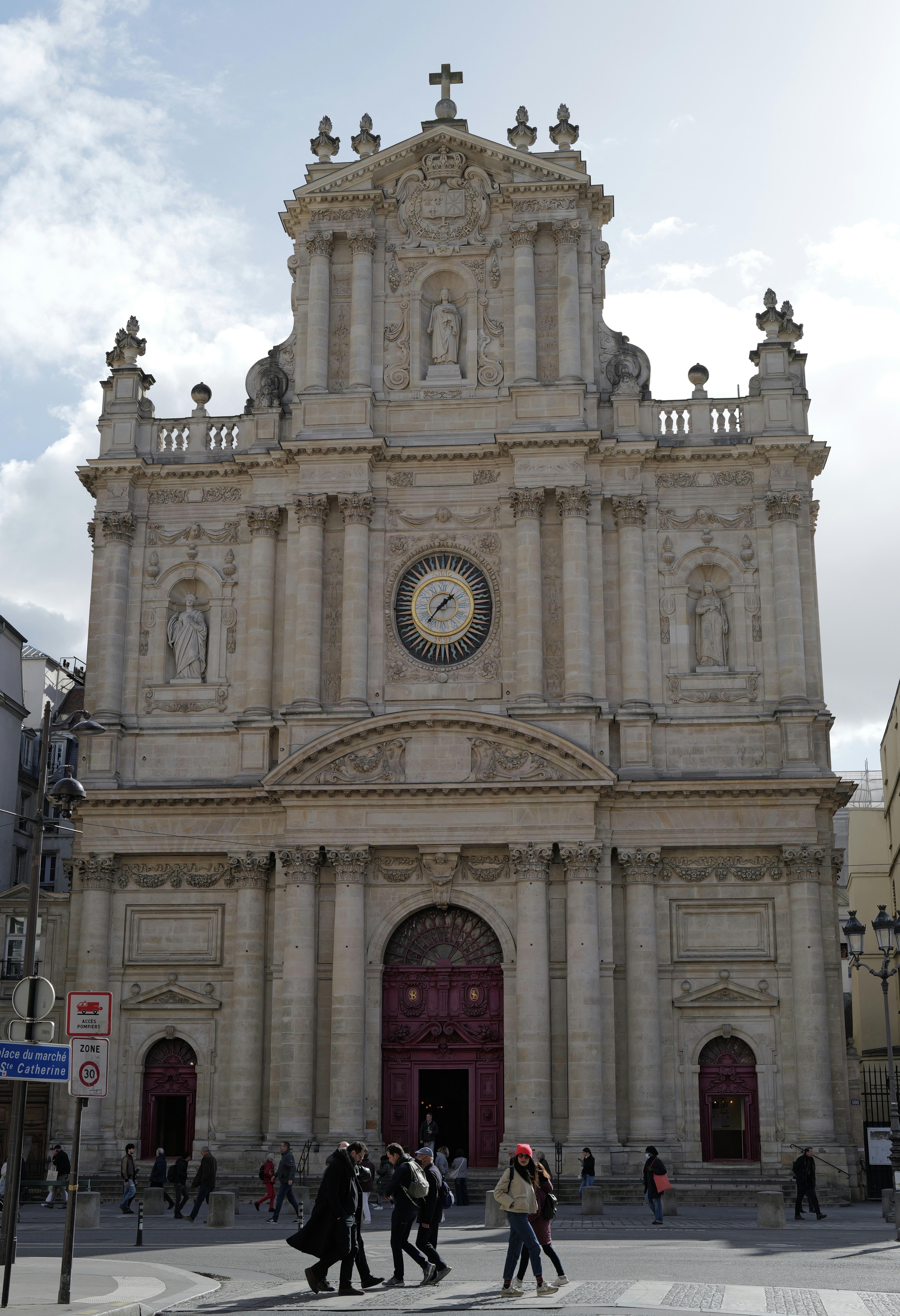 Facade of the Baroque church crowned by statues and a central clock