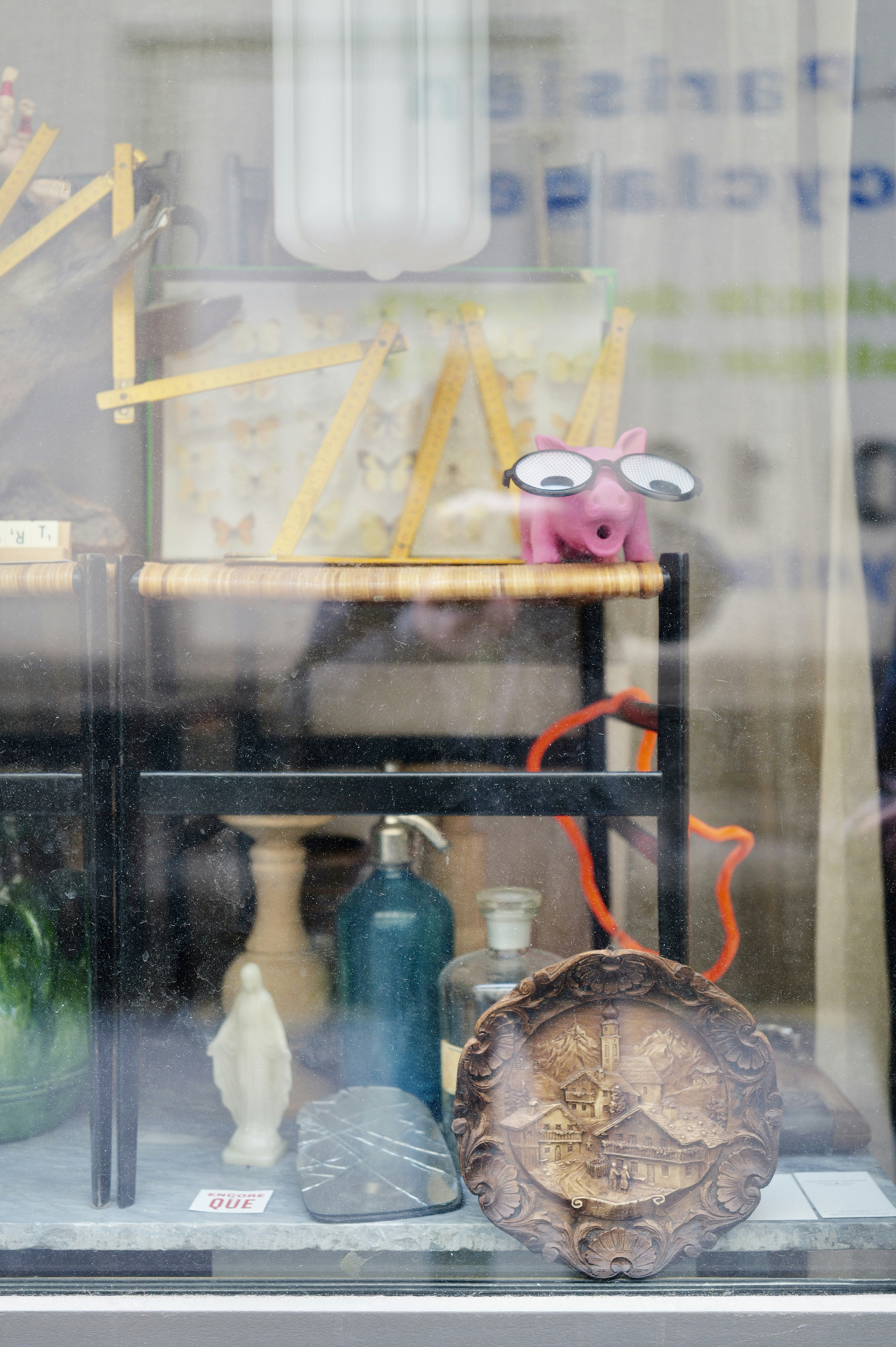 Glass Shop Window Whimsy: Pink Pig with Glasses Over a Shelf of Treasures