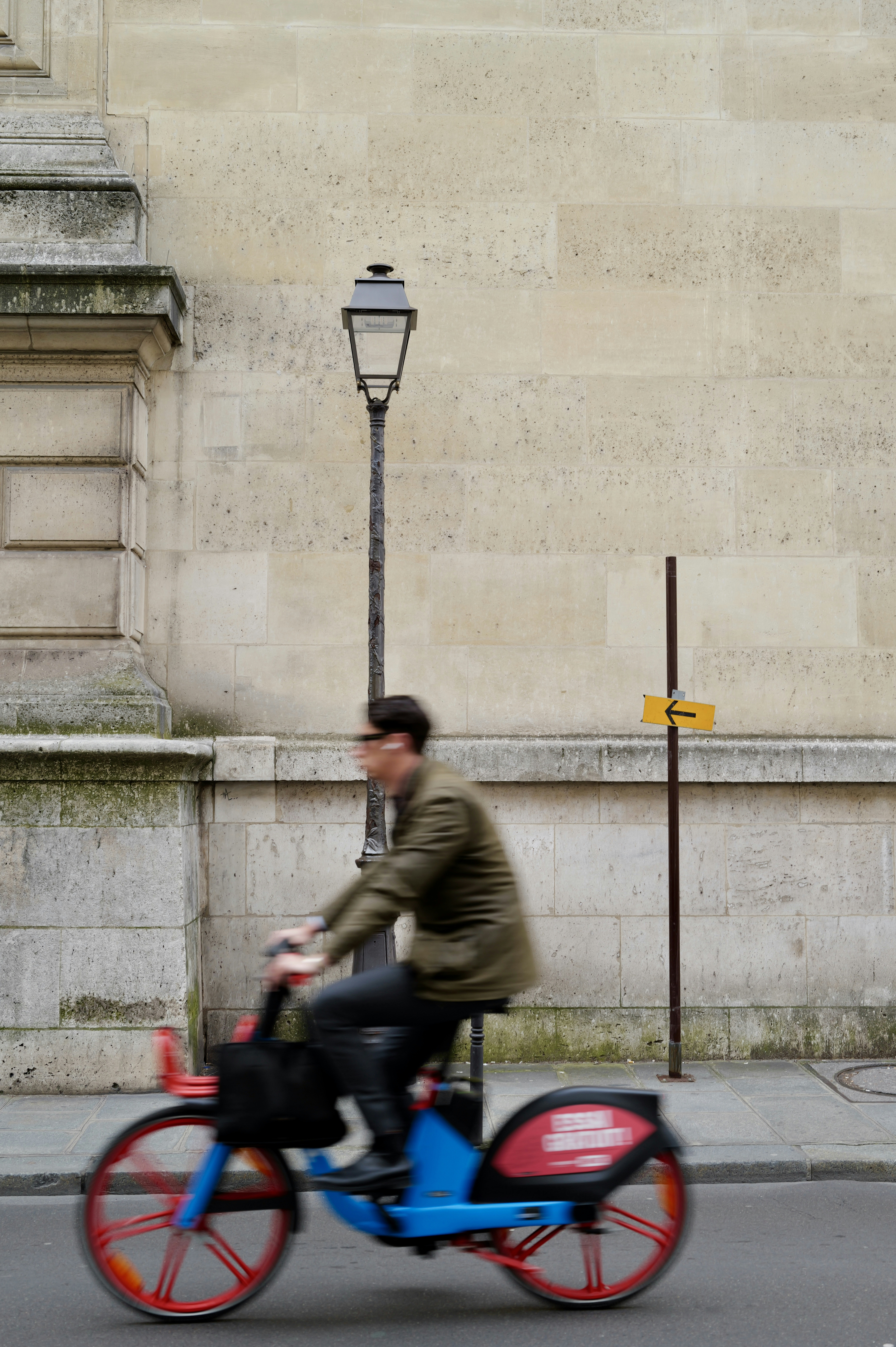 Urban Glide: a cyclist in motion past a historic stone wall