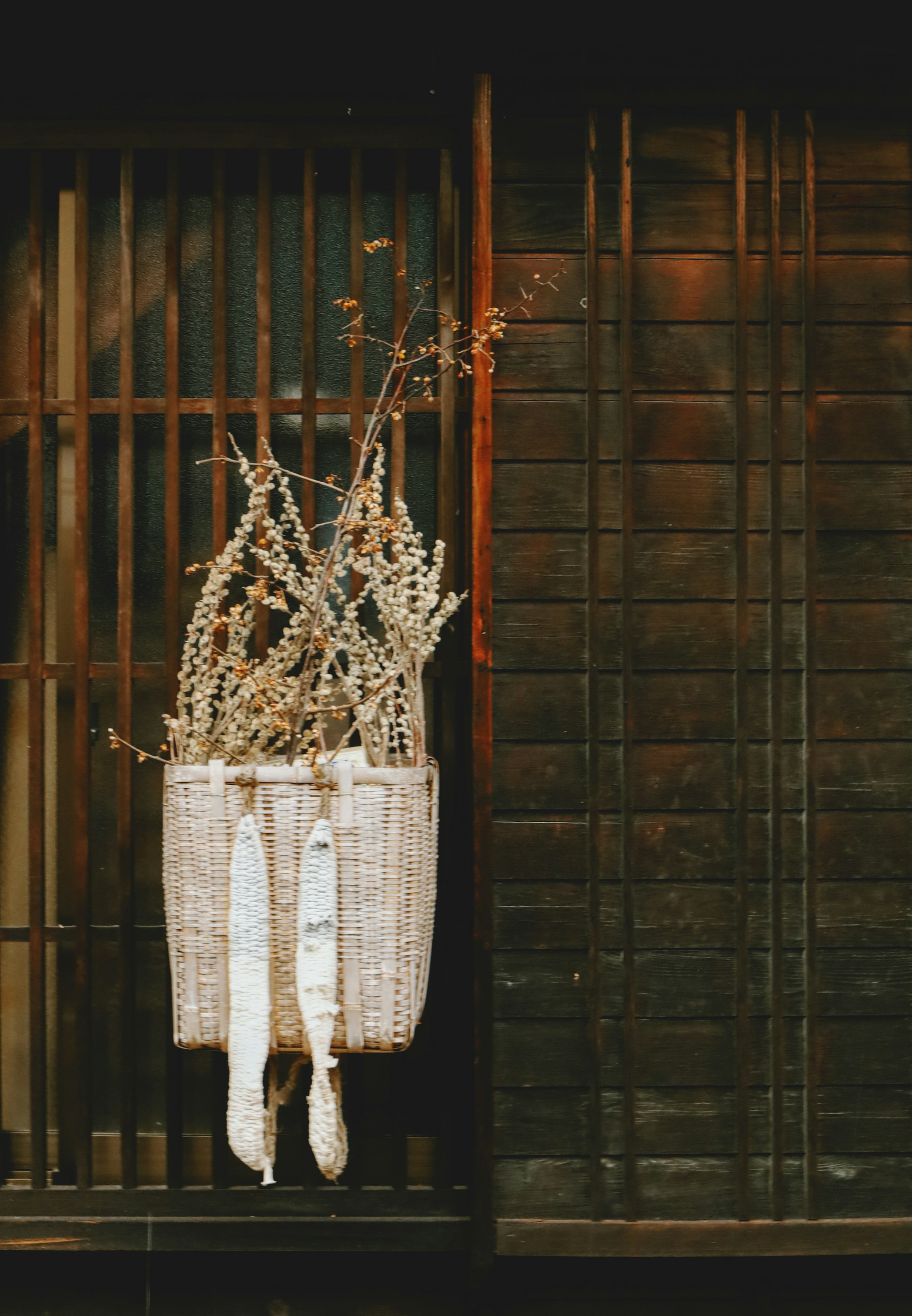 Weaving Silence: Dried Sprigs in a Rustic Basket against Wood Slats