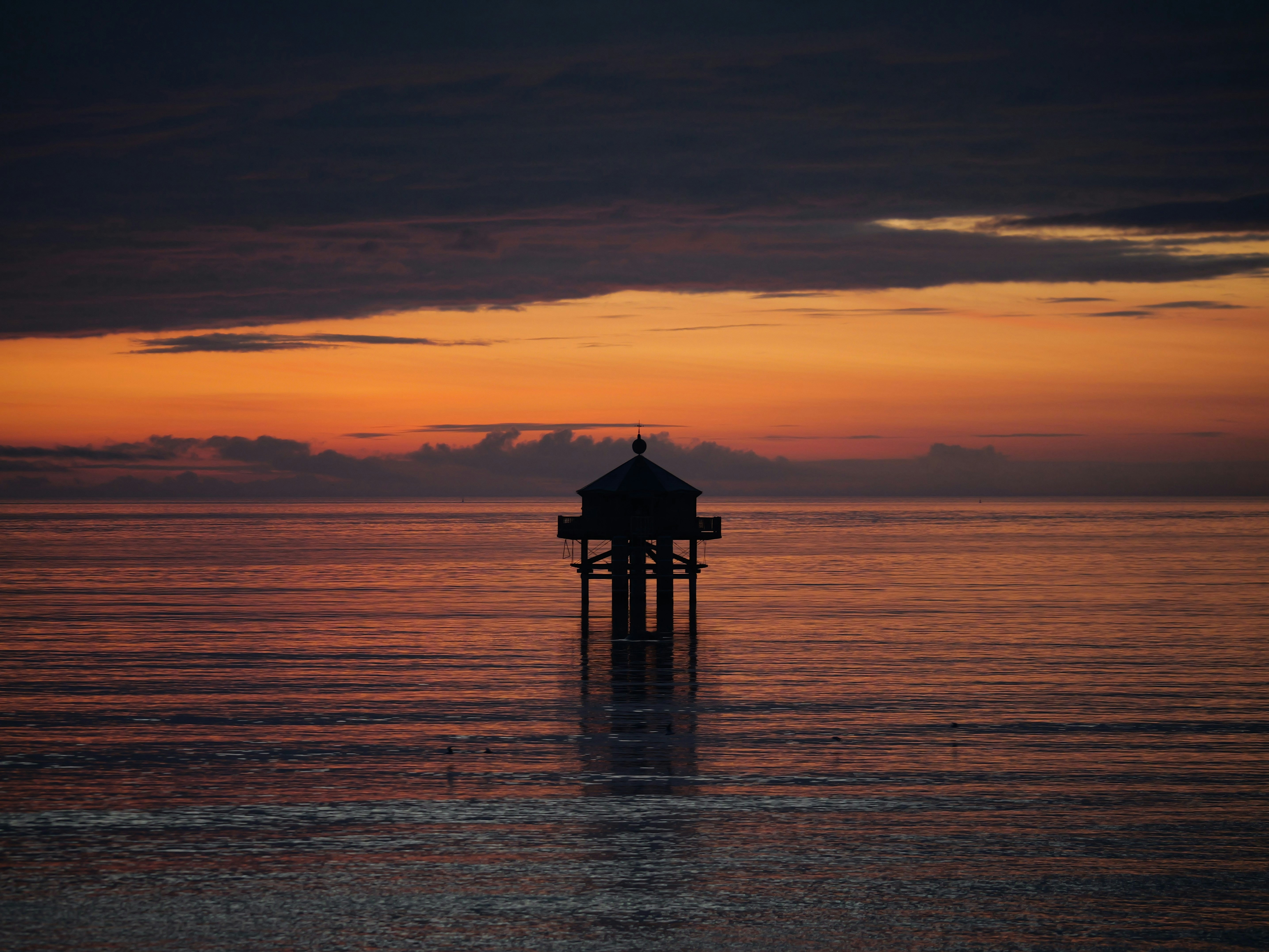 Silhouette at Dusk: A solitary pier-temple over a tranquil sea