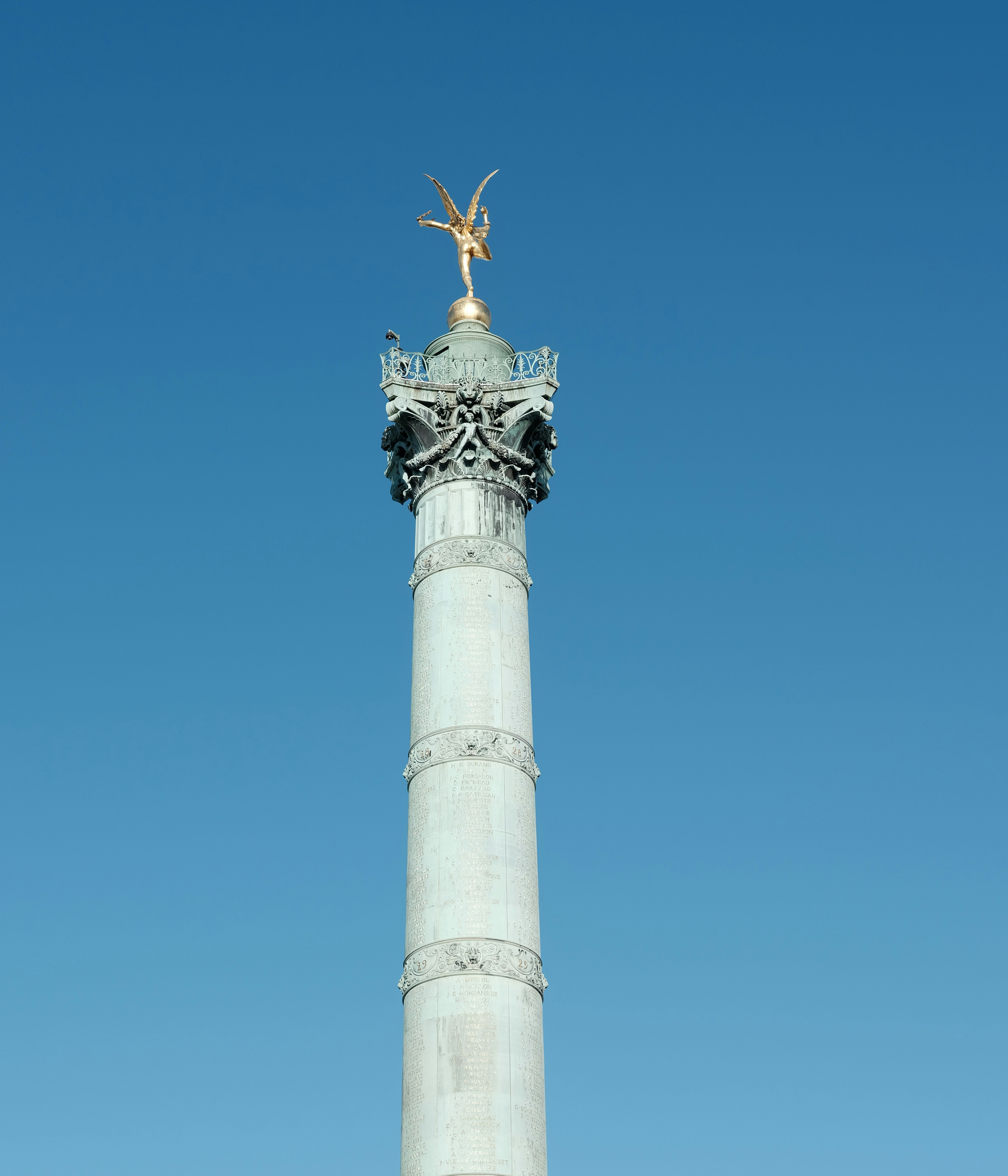 Golden Angel atop a Marble Column under a Clear Sky