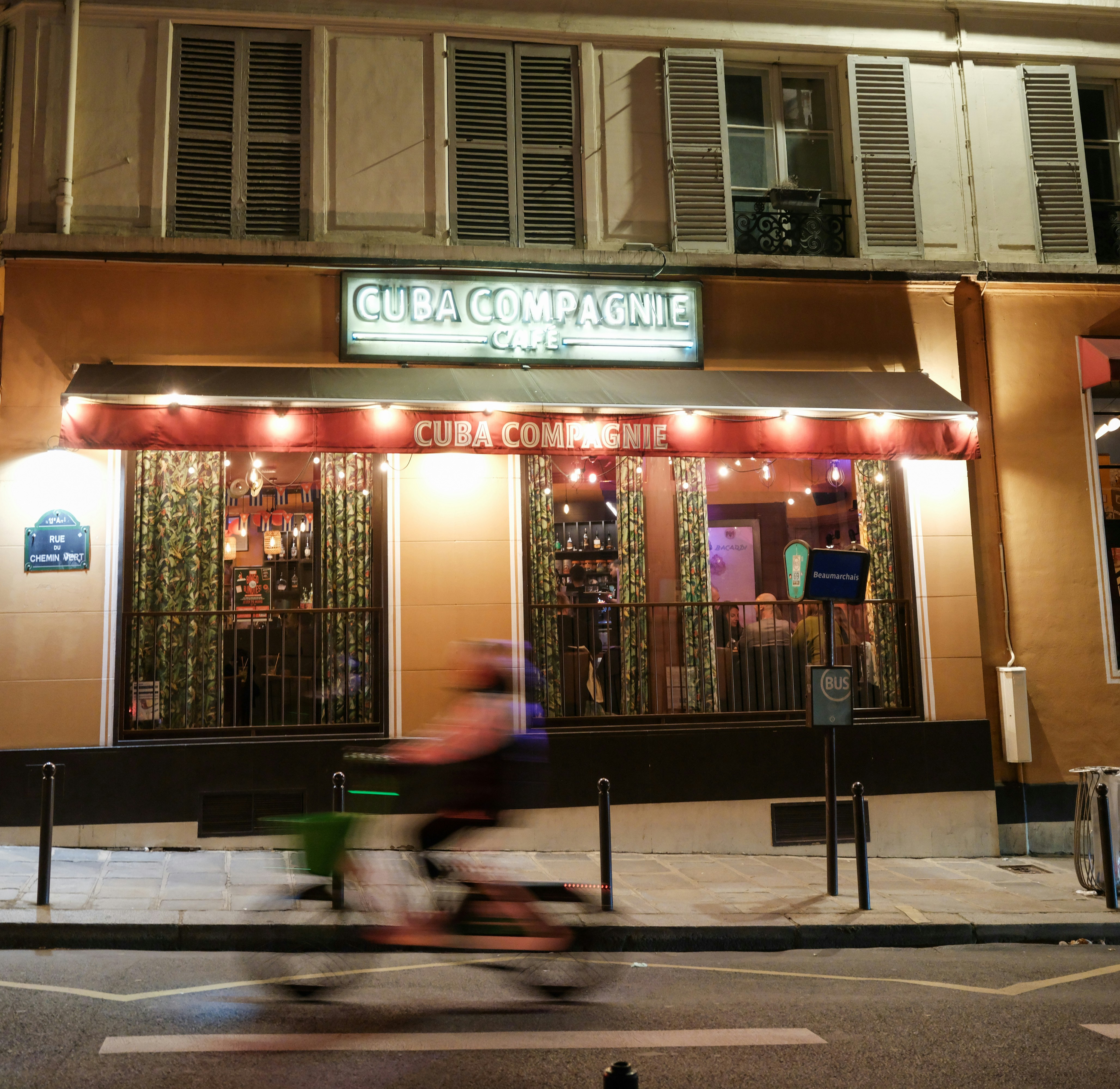Neon Signage and Blurred Bicycle in Front of Cuba Compagnie Café