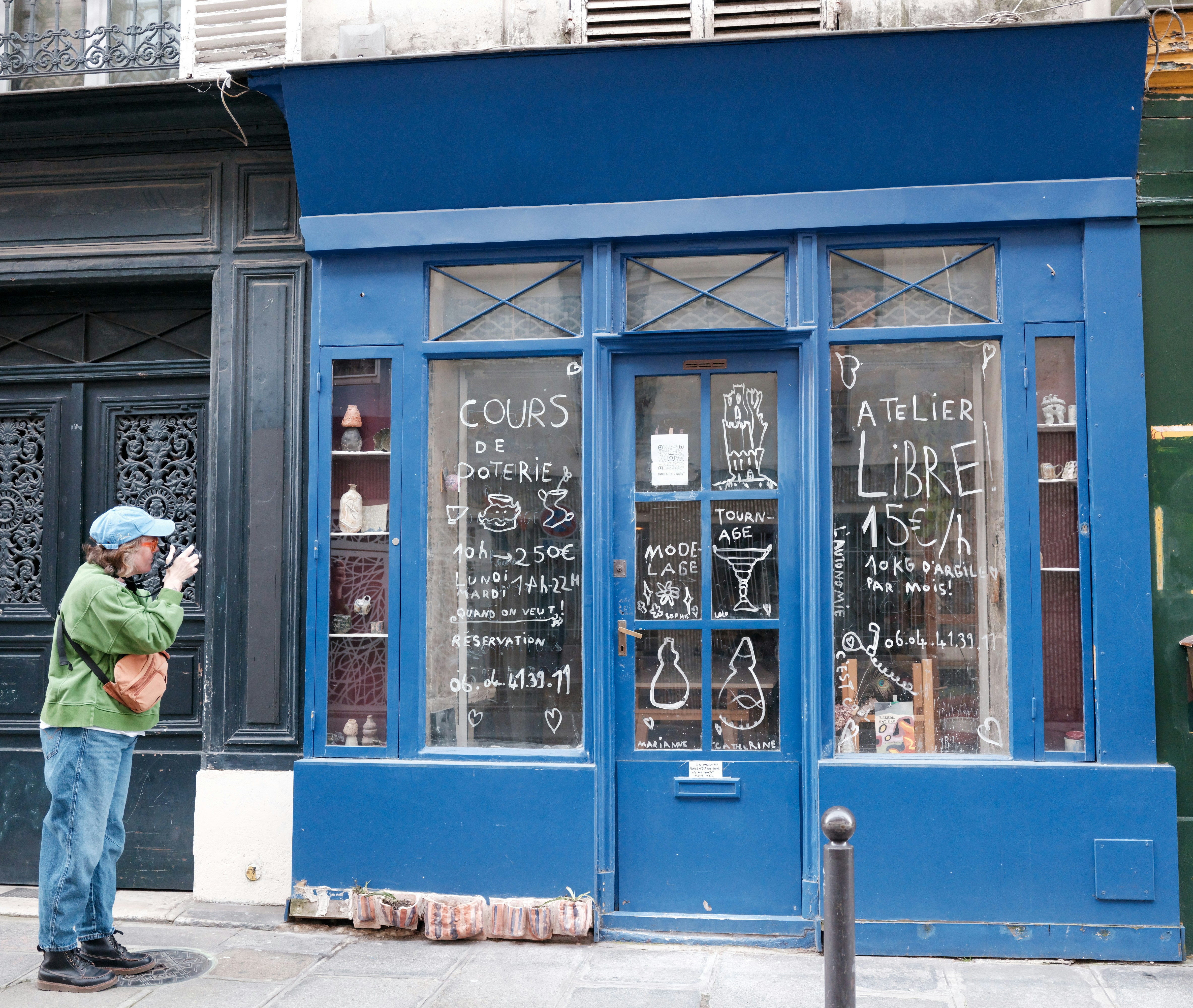 Blue storefront portrait: a photographer frames a street scene with a curious visitor
