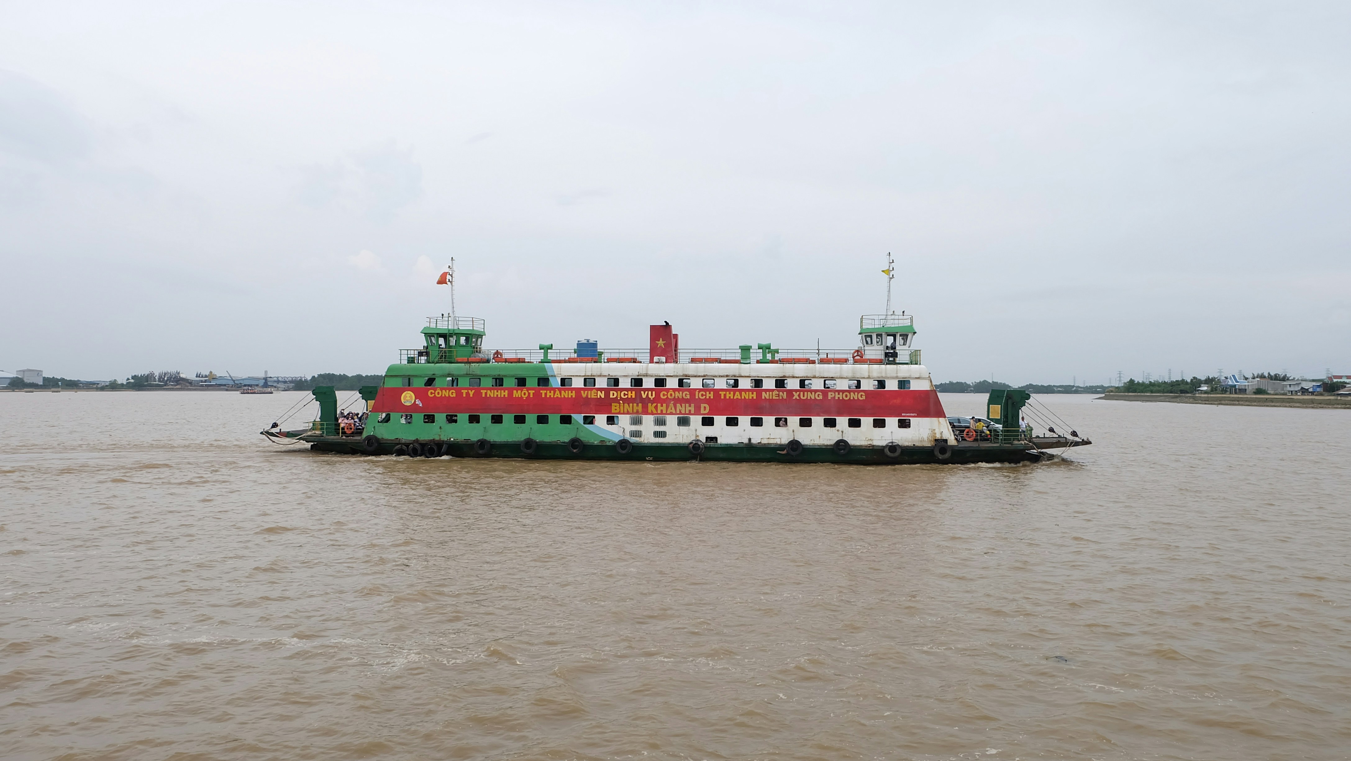 Colorful river ferry gliding across a muddy brown current