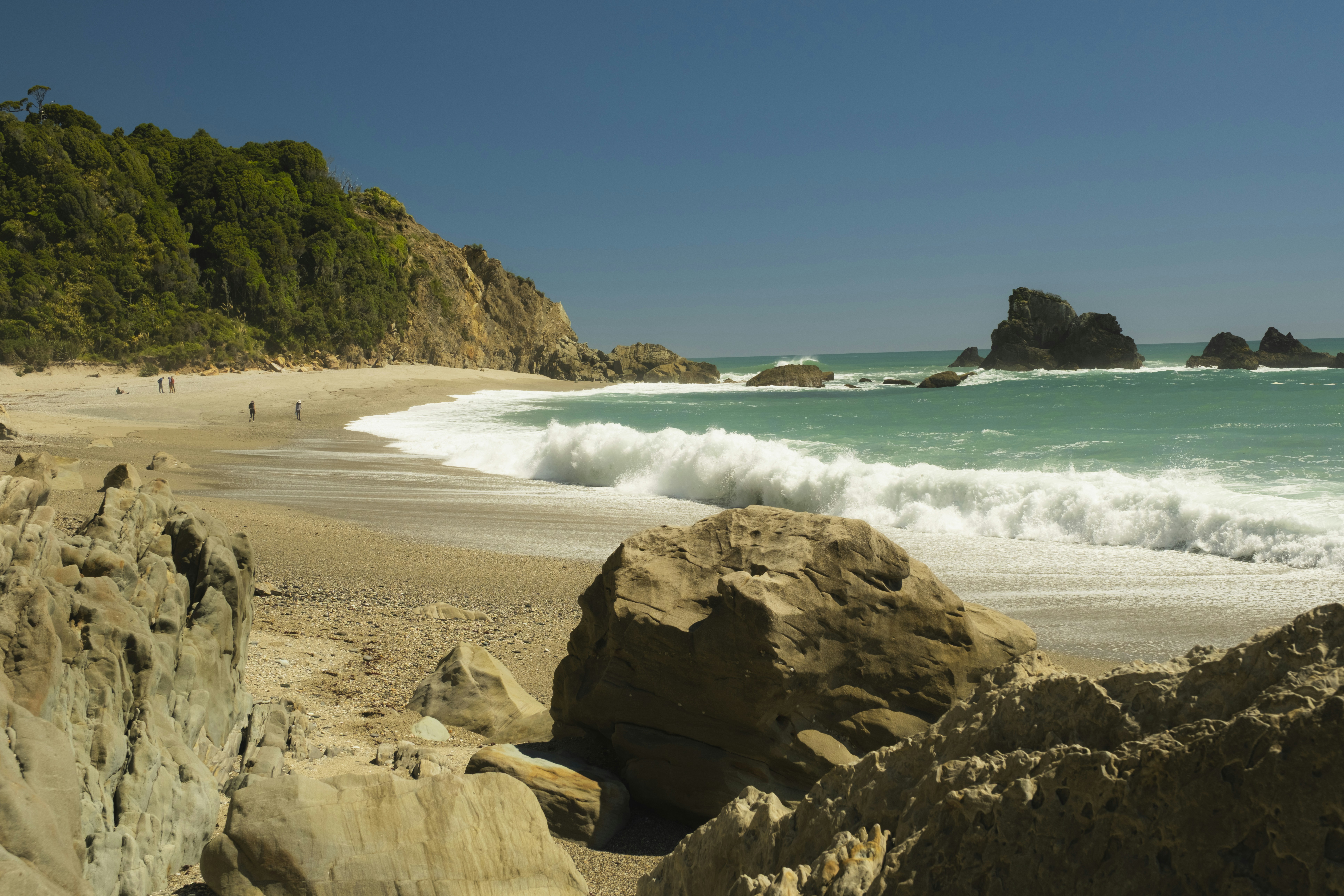 Coastal Promenade: Sunlit Beach Between Weathered Rocks