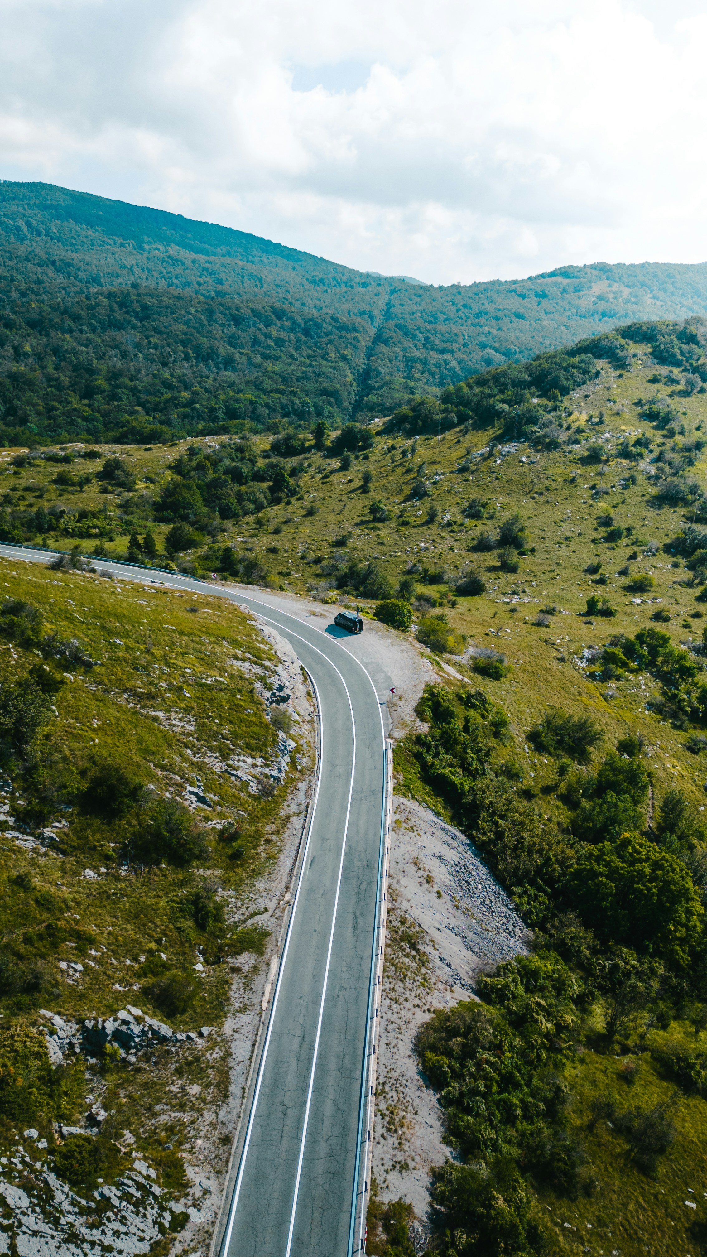 Curved Mountain Road: A Solo Car Traverses a Winding Pass